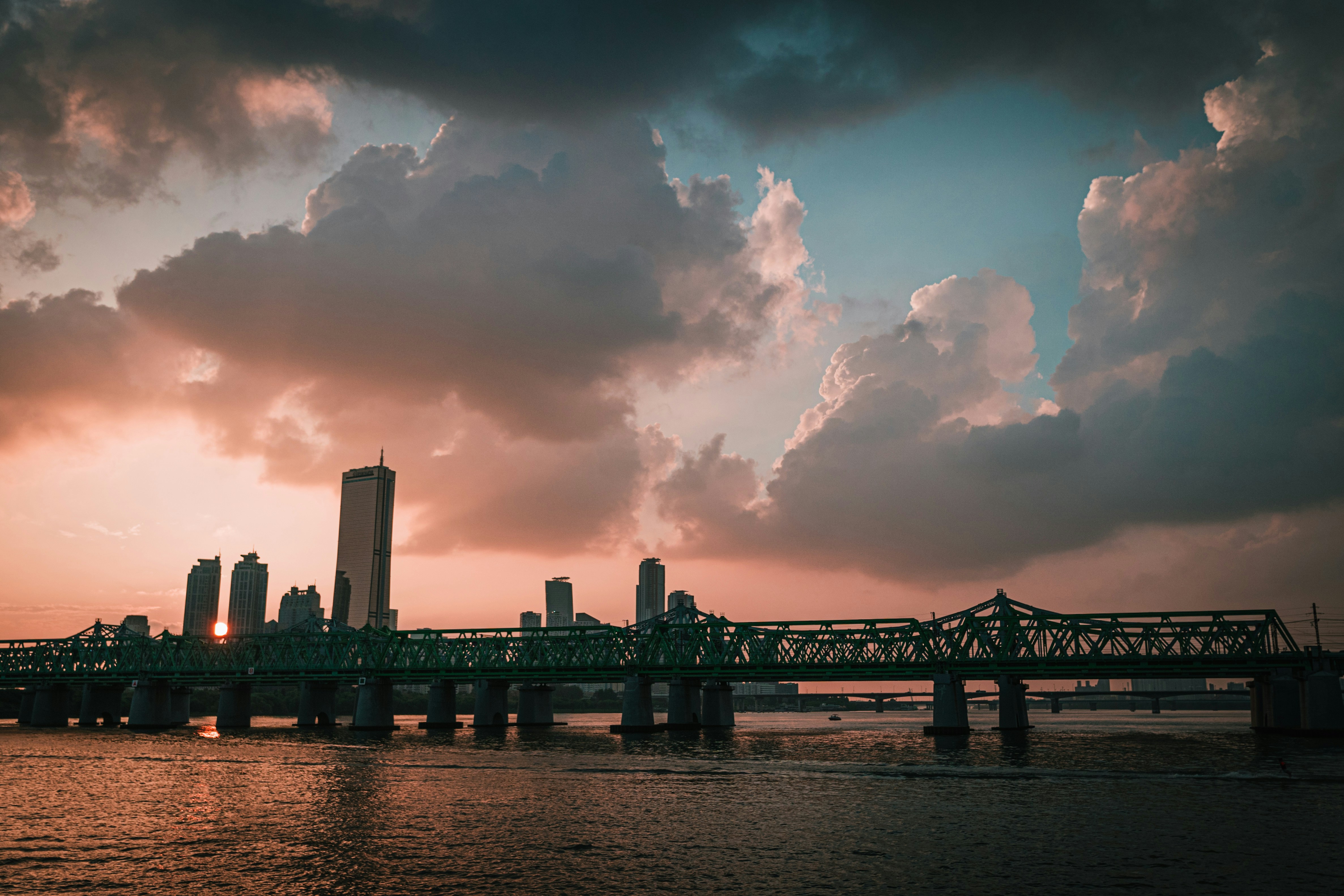 Sunset Over the Riverfront: Skyscraper Silhouette Beyond the Bridge
