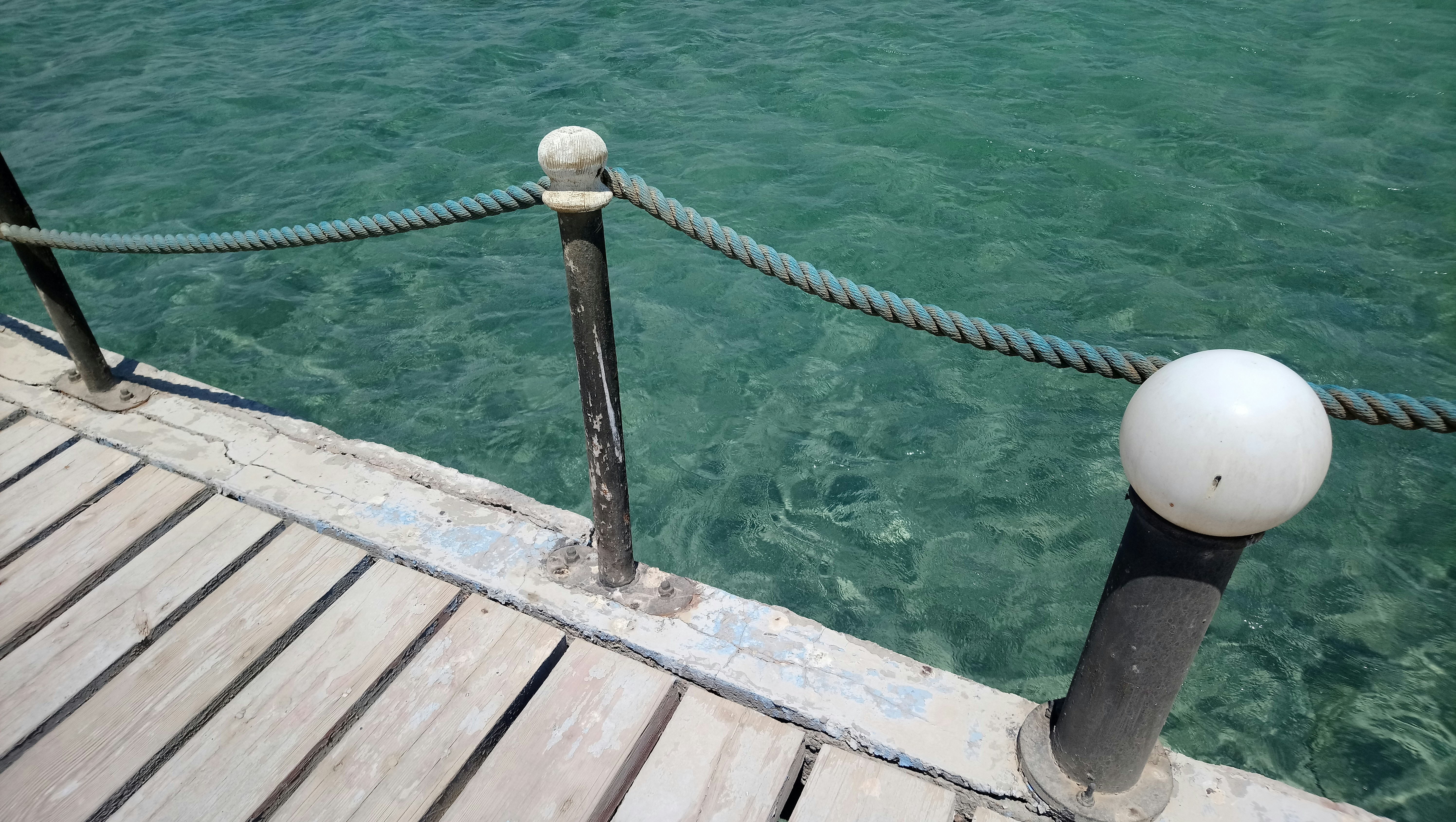 Wooden dock railing with a clear view of turquoise waters beneath a sunny sky.