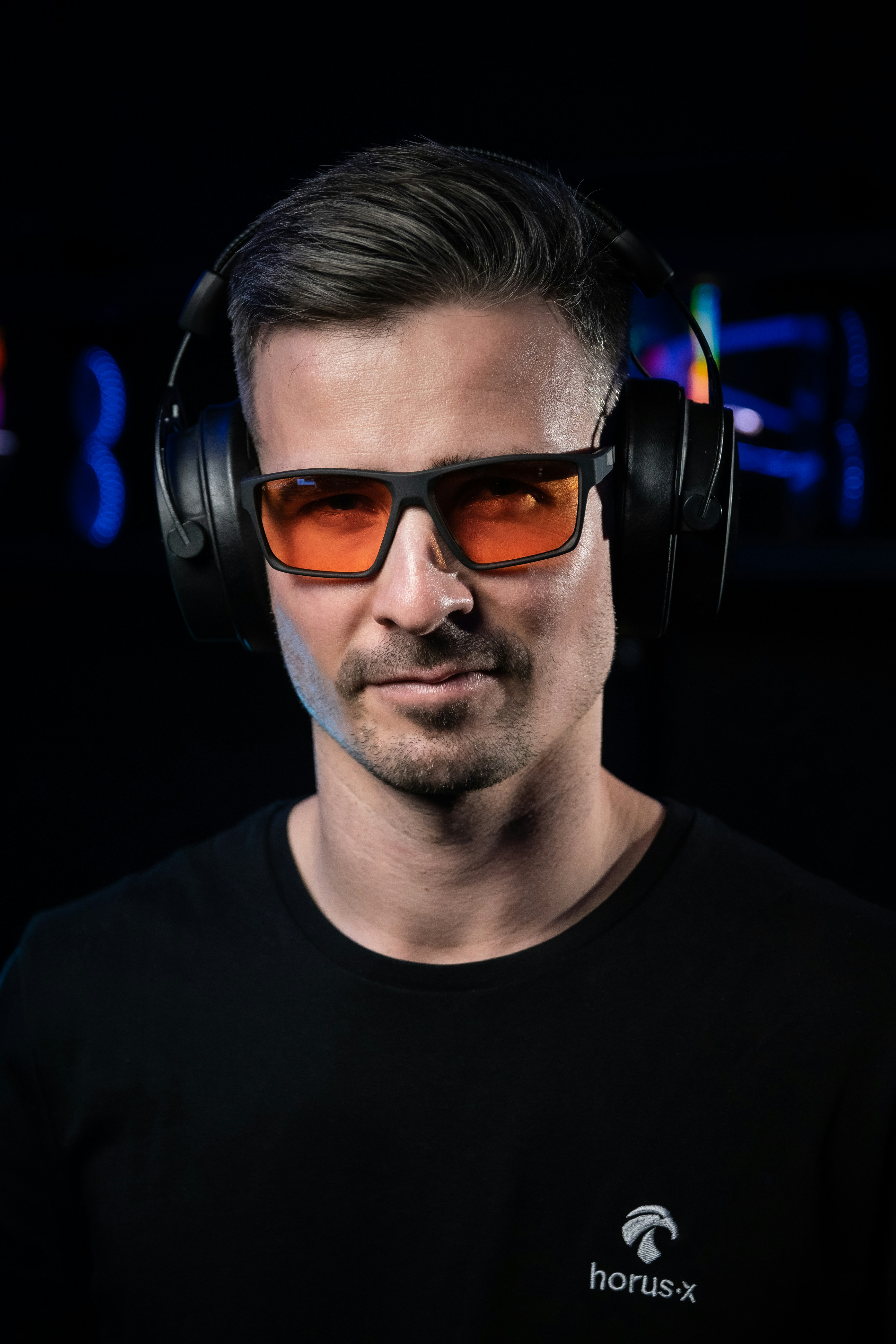 Man wearing orange glasses and headphones looking at camera
