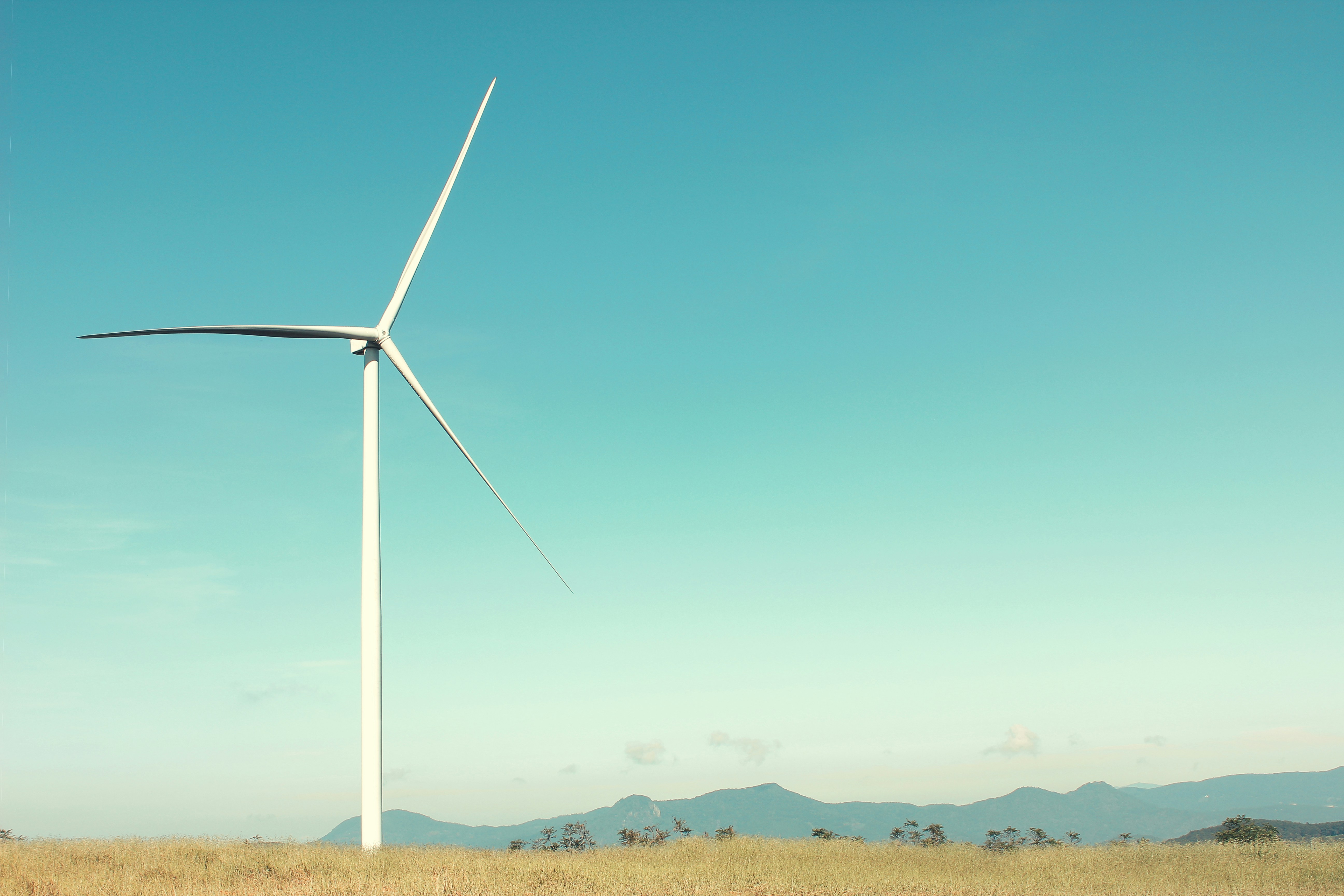 A lone wind turbine stands in a dry field.