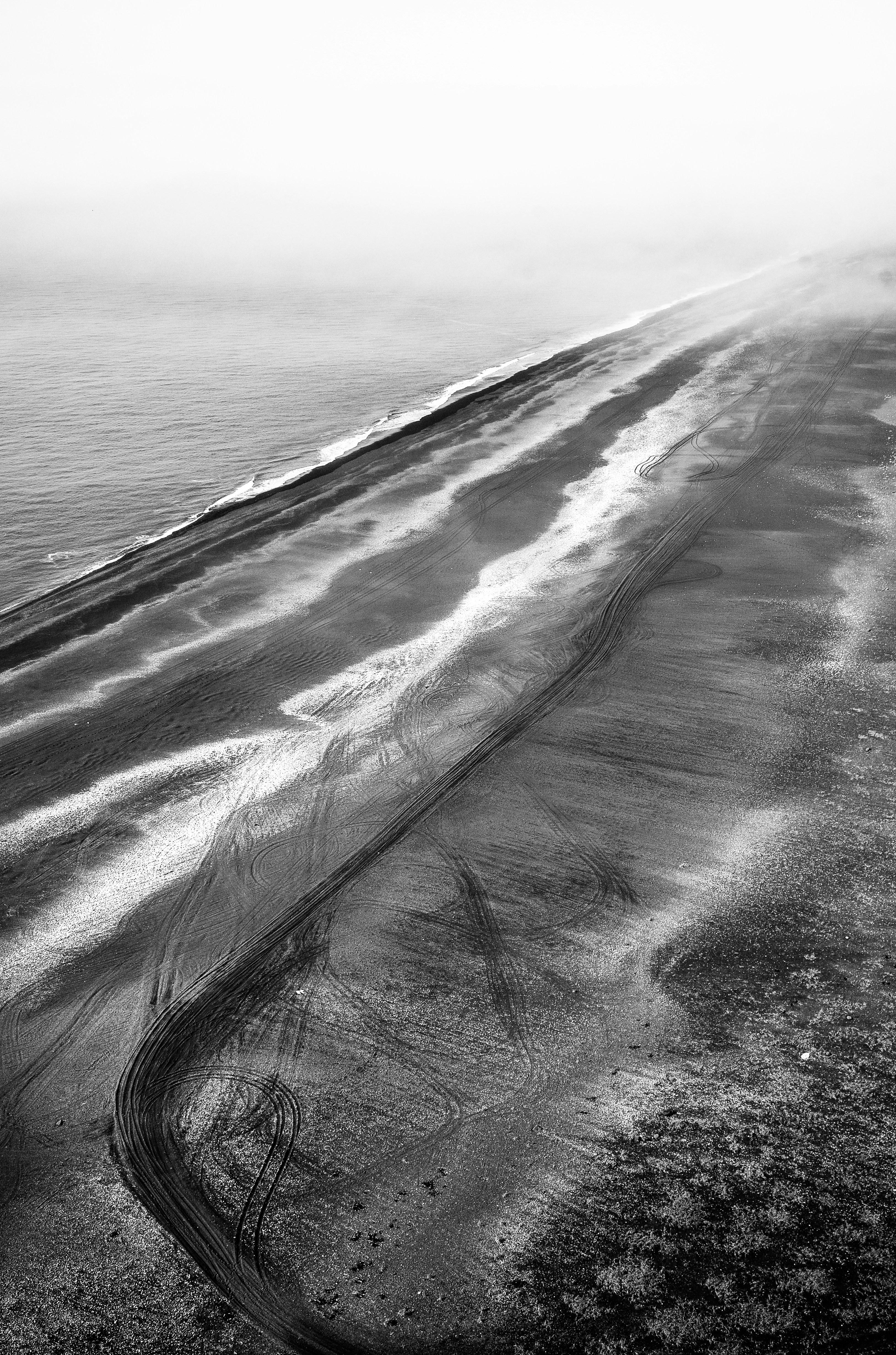 Misty beach with tire tracks along the shore