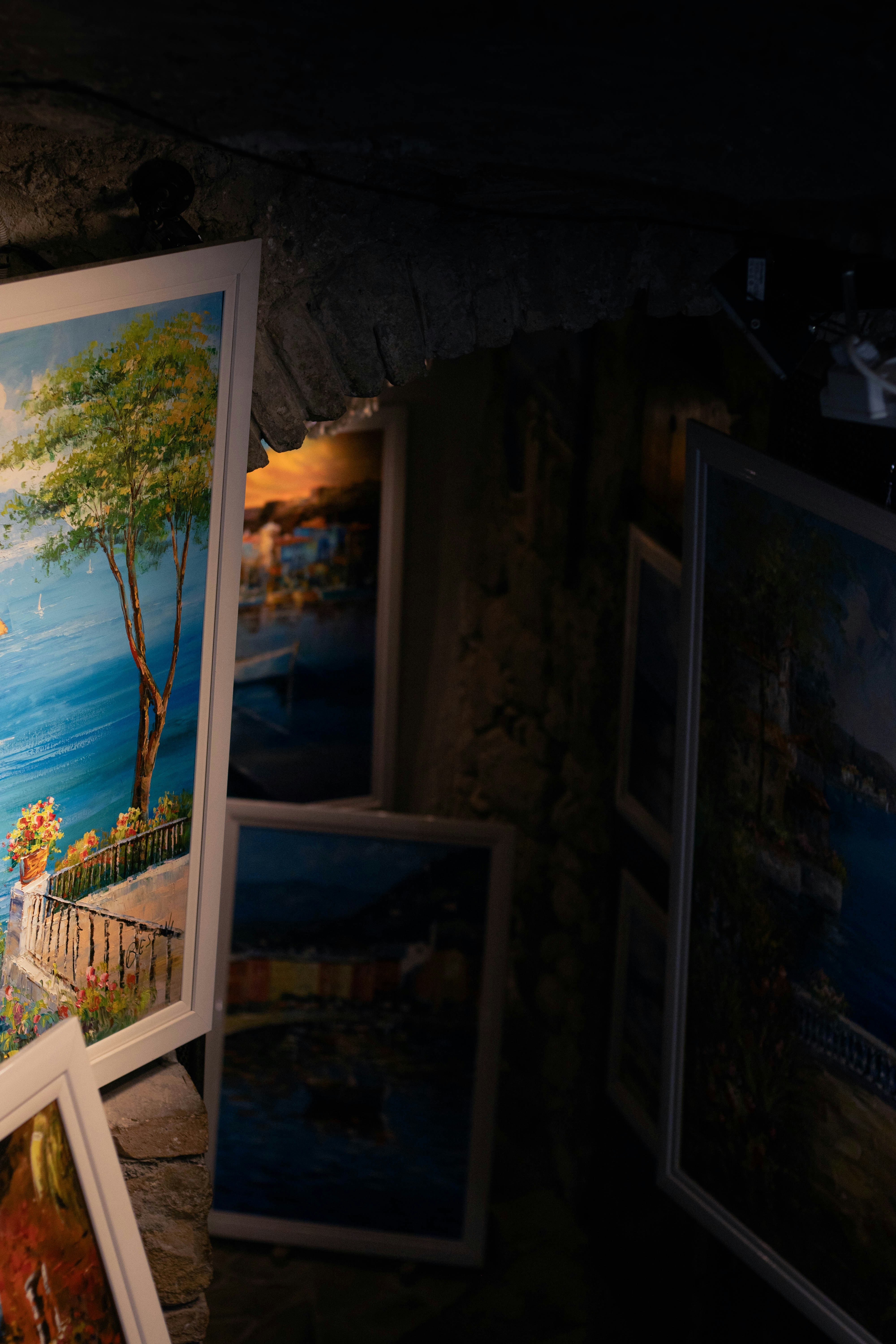 Several framed paintings displayed on a stone wall.