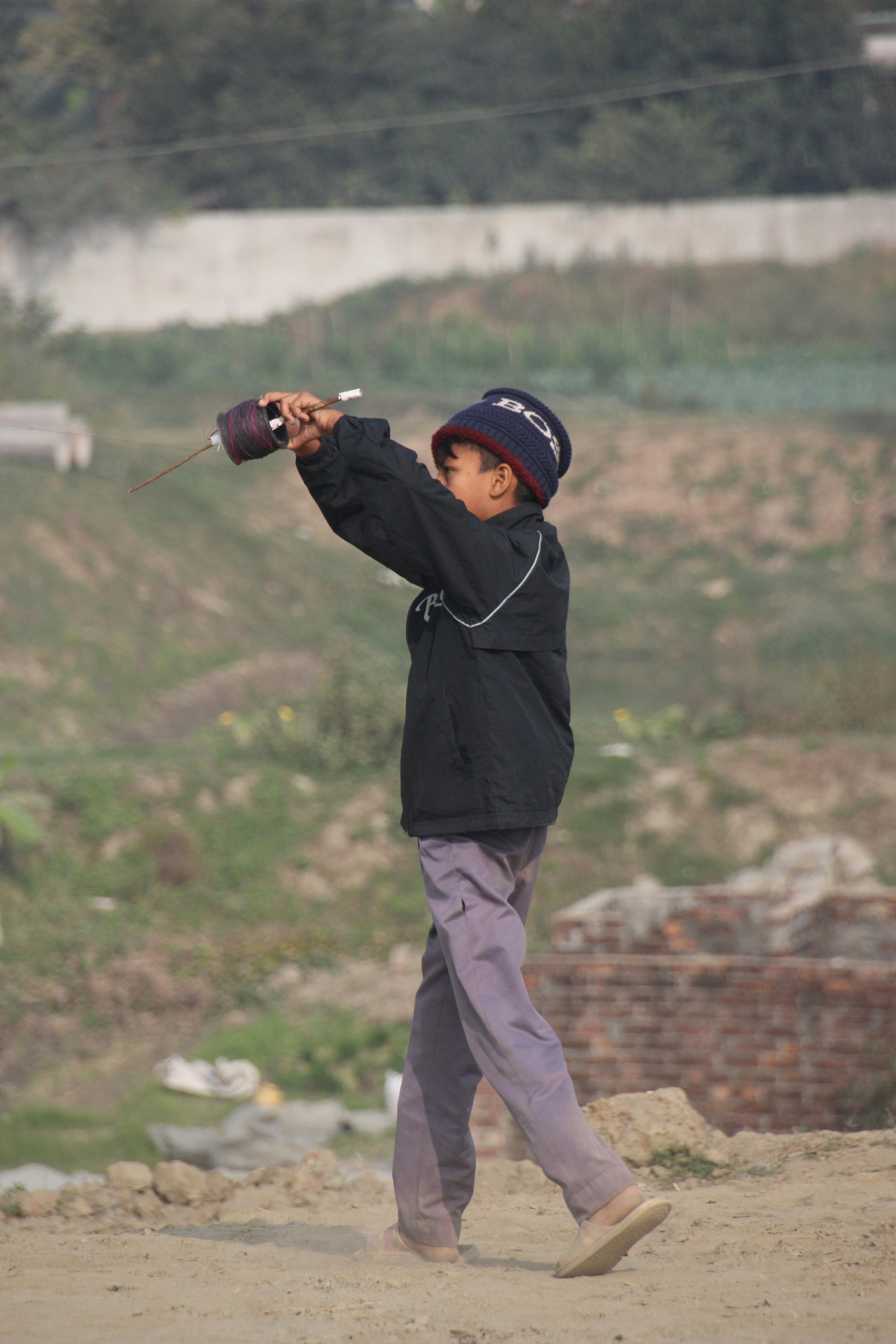 Aiming at Quiet Horizons: Boy with a Homemade Twig Toy in a Dusty Open Field