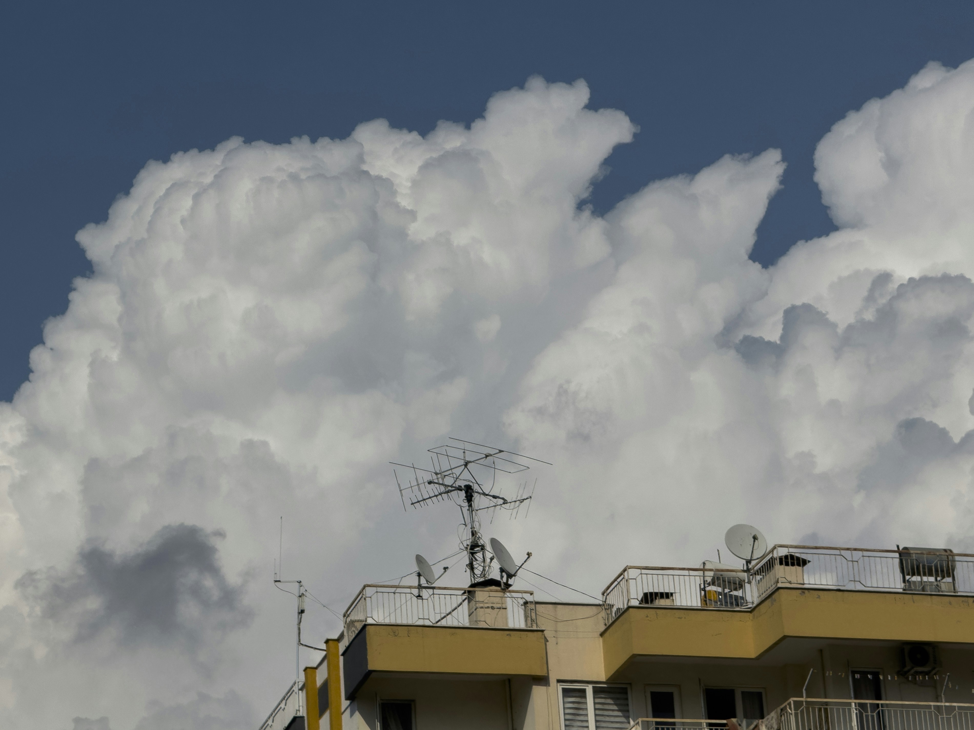 fluffy clouds over urban building | Large white clouds over apartment building rooftops.