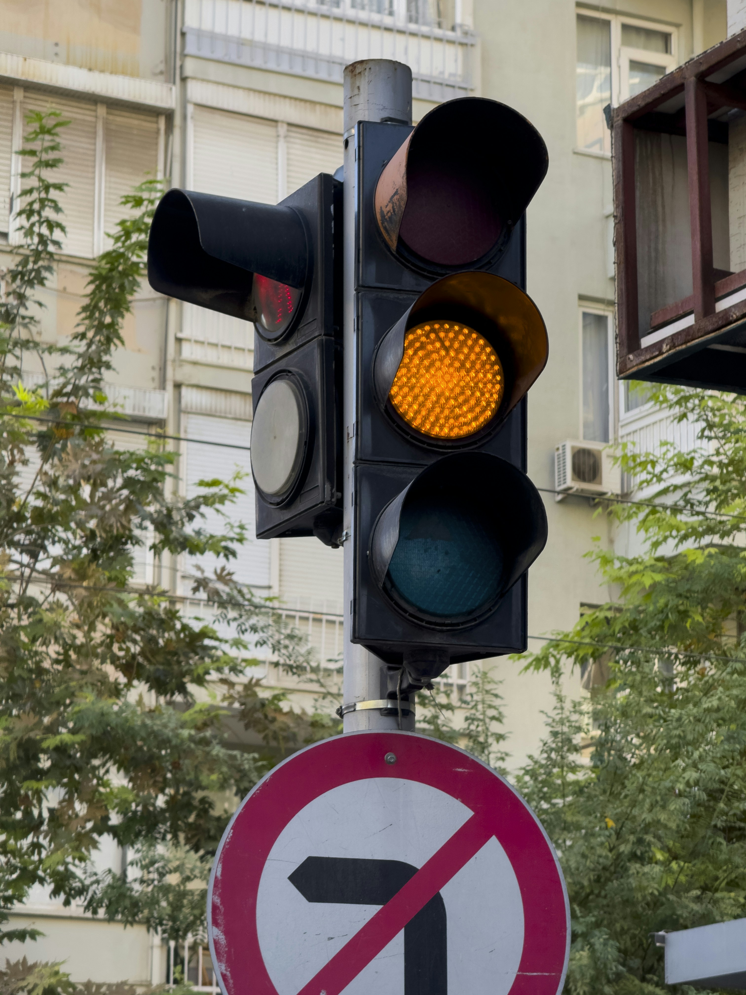 glowing yellow light on street | Traffic light shows yellow with no left turn sign.