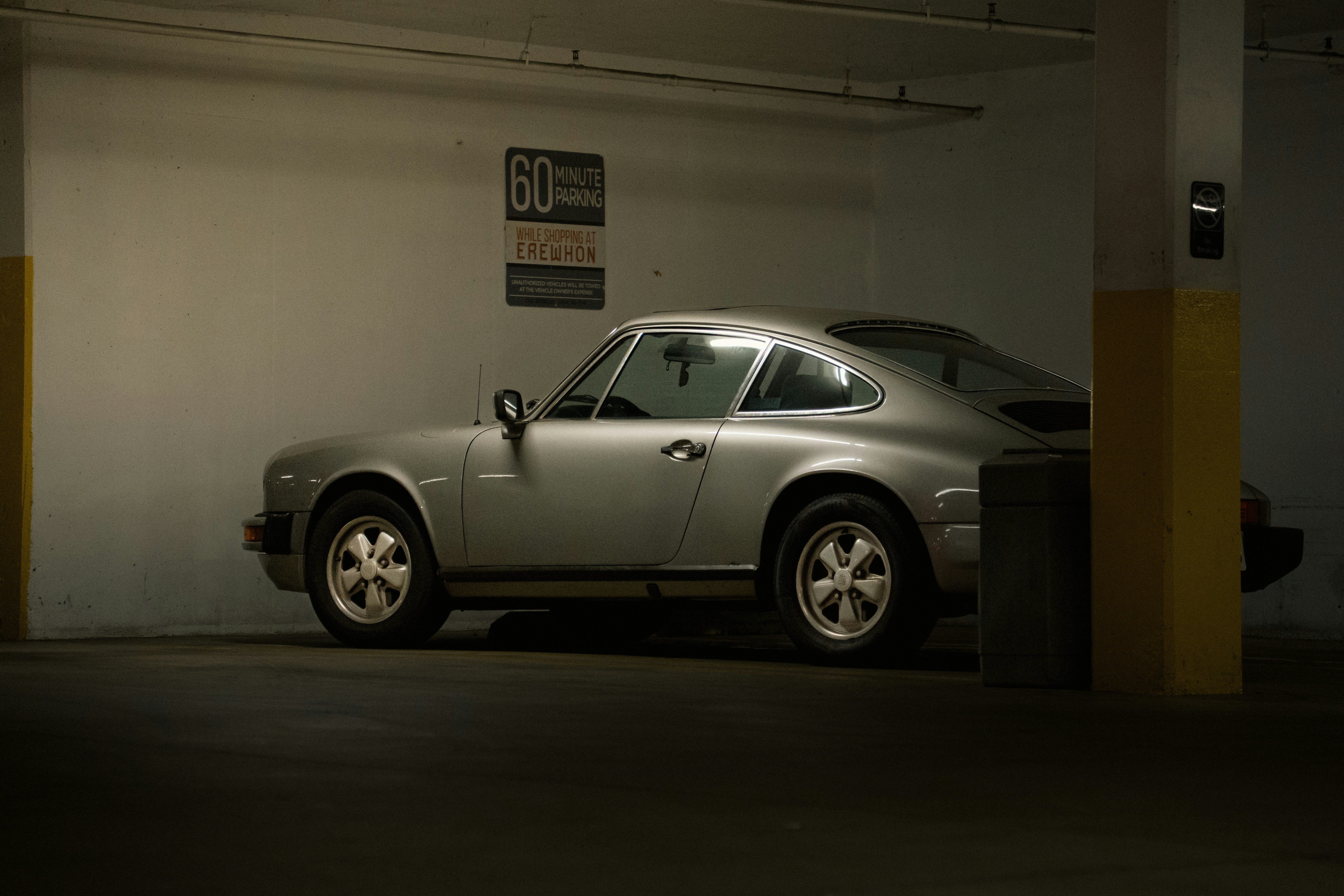 Classic silver sports car parked in a dimly lit garage, illuminated by soft light. The scene evokes nostalgia and elegance.