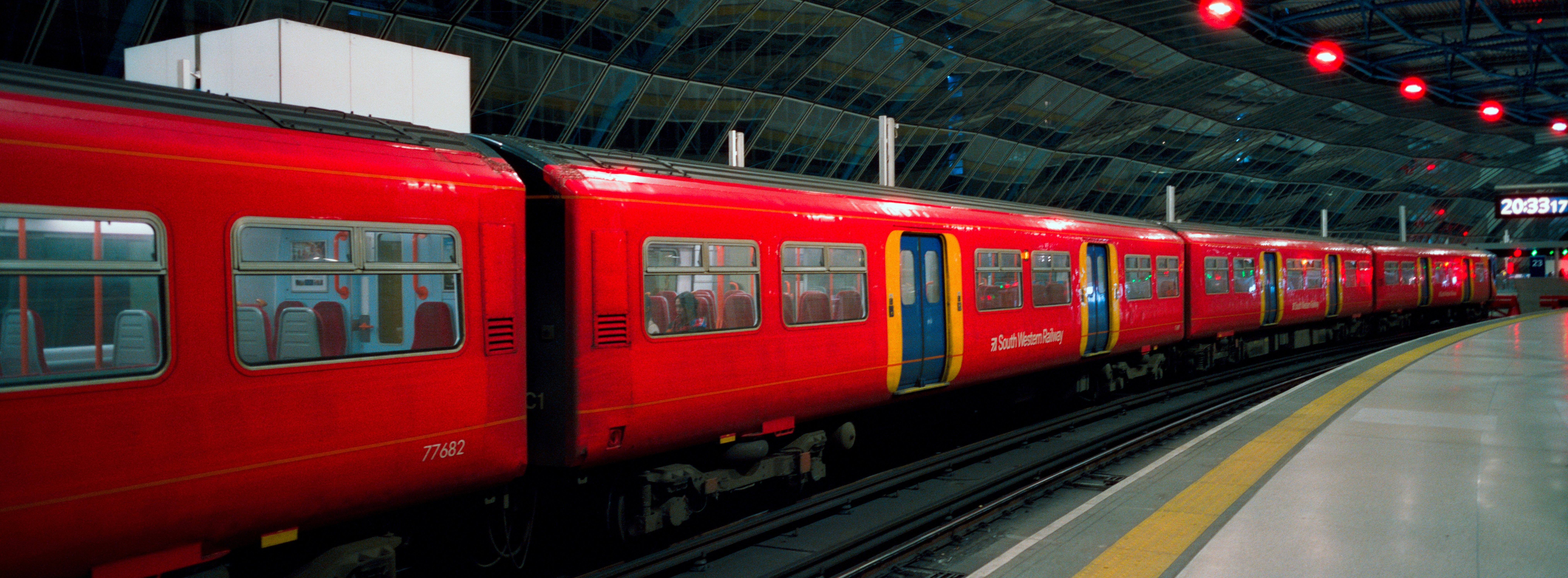 London's Waterloo Station, vibrant red train at night, capturing urban movement and energy.