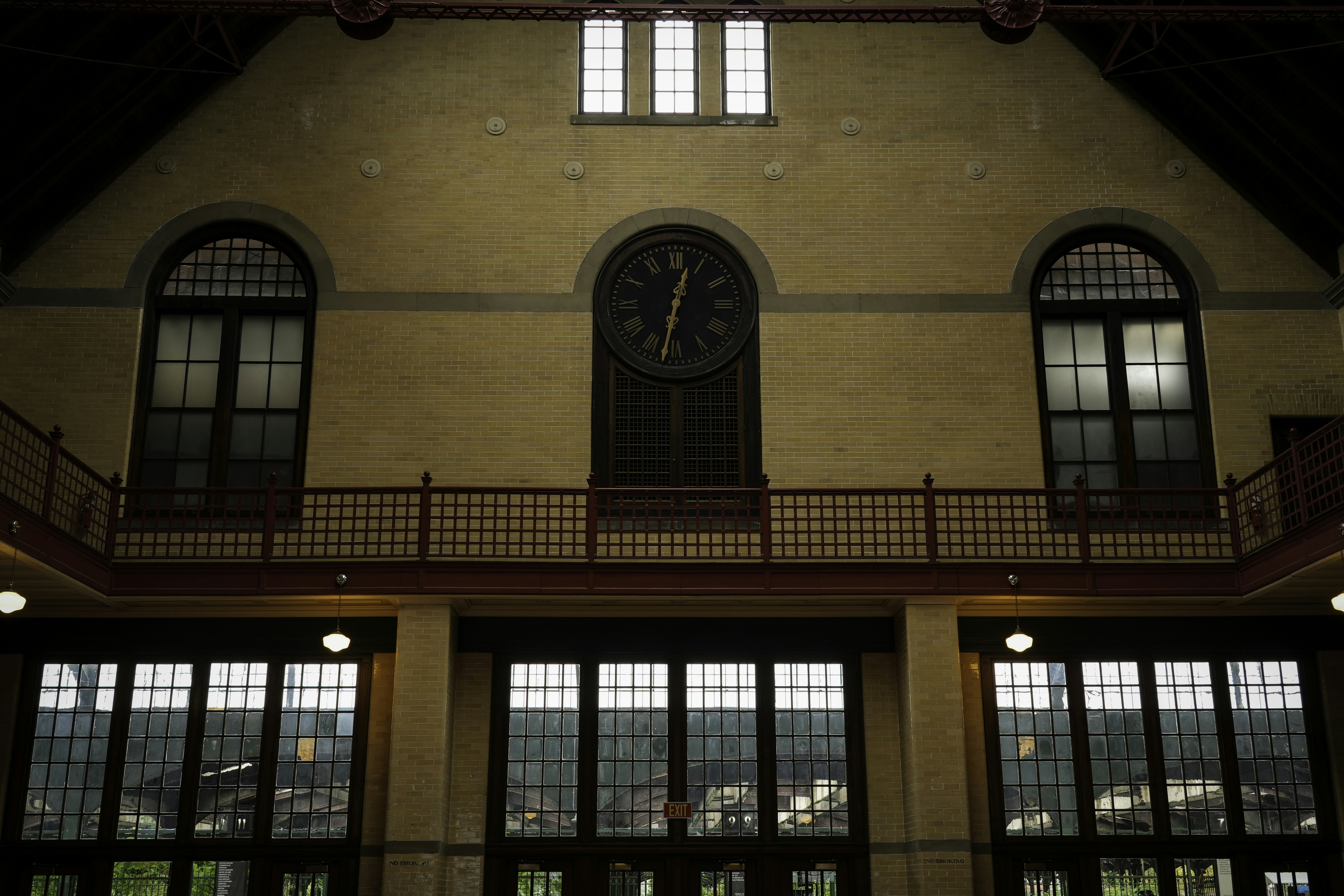 Historic train station interior featuring large windows, a prominent clock, and intricate architectural details.