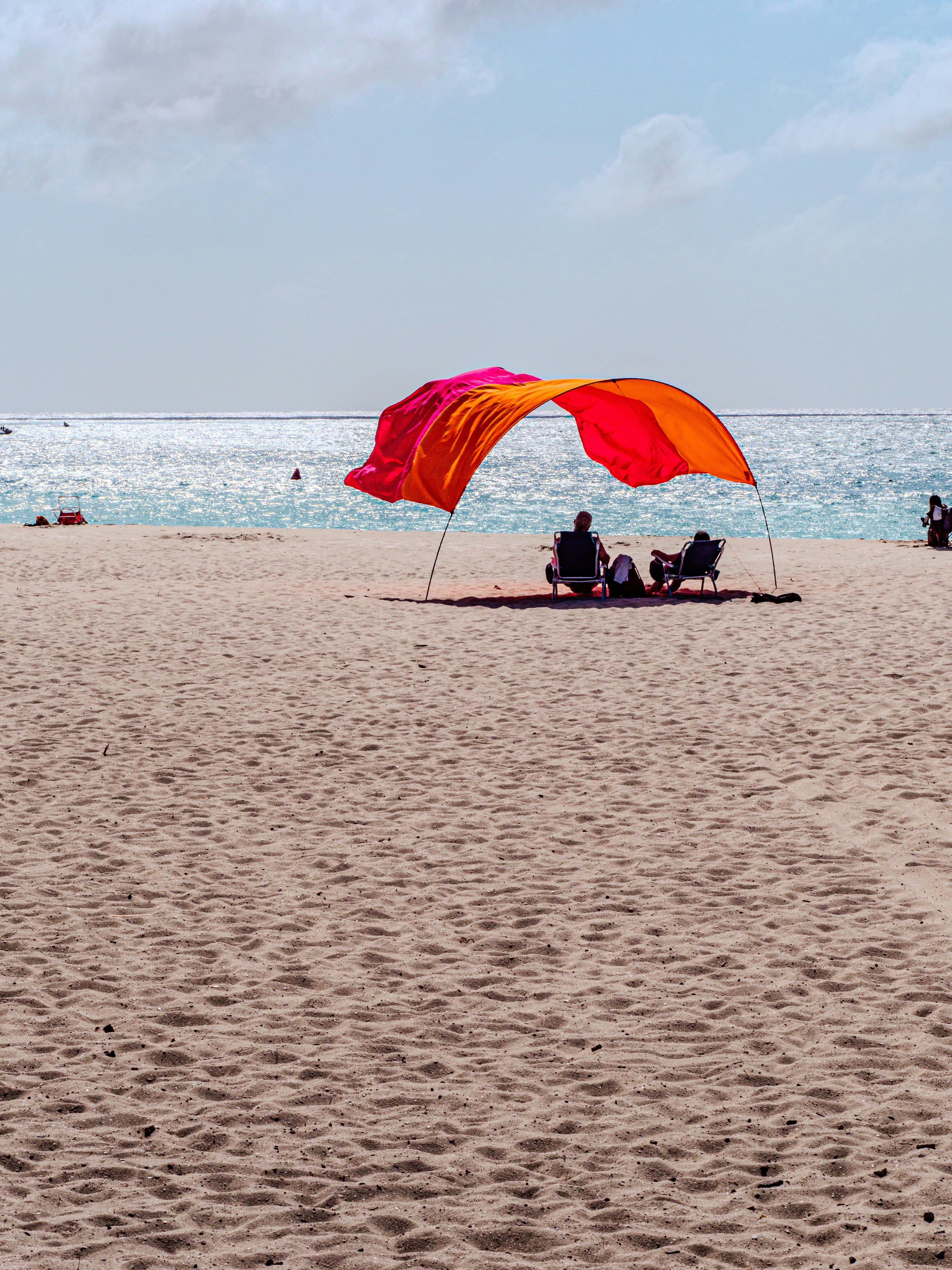 Coral Canopy Retreat: A Beach Moment under a Fiery Shade