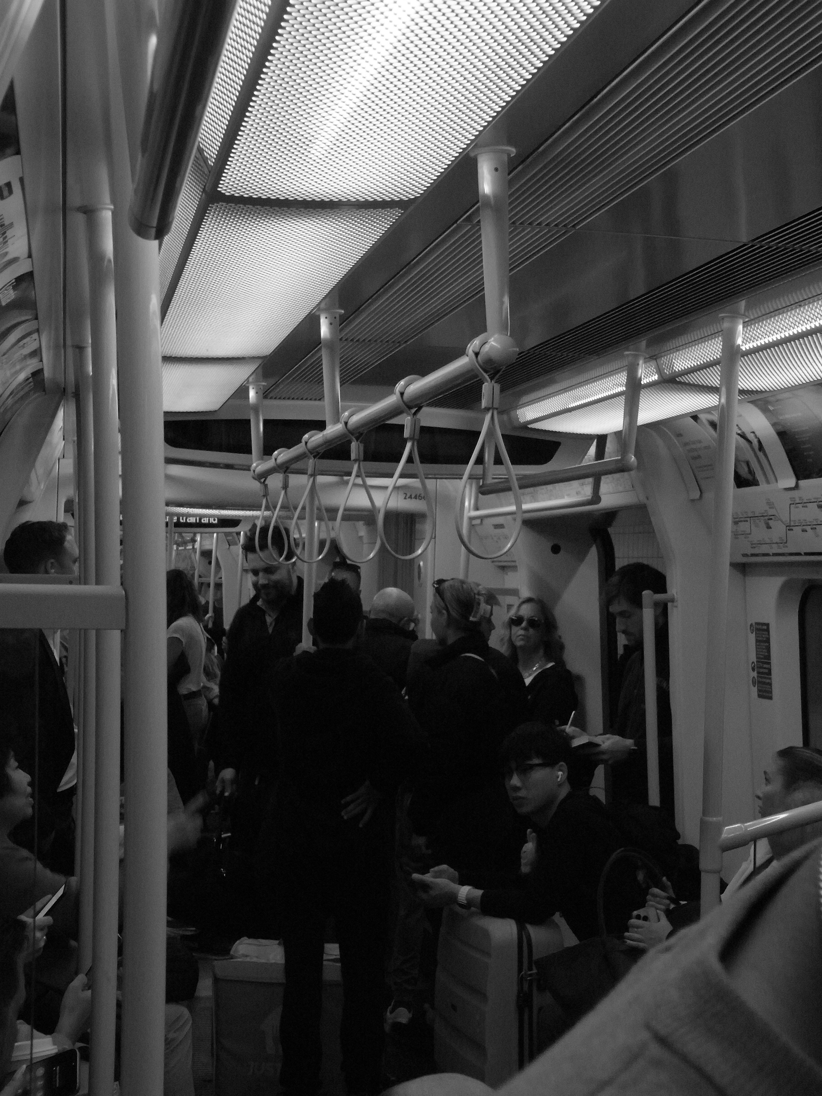 A bustling subway interior filled with commuters, showcasing the everyday life of city dwellers in monochrome tones.