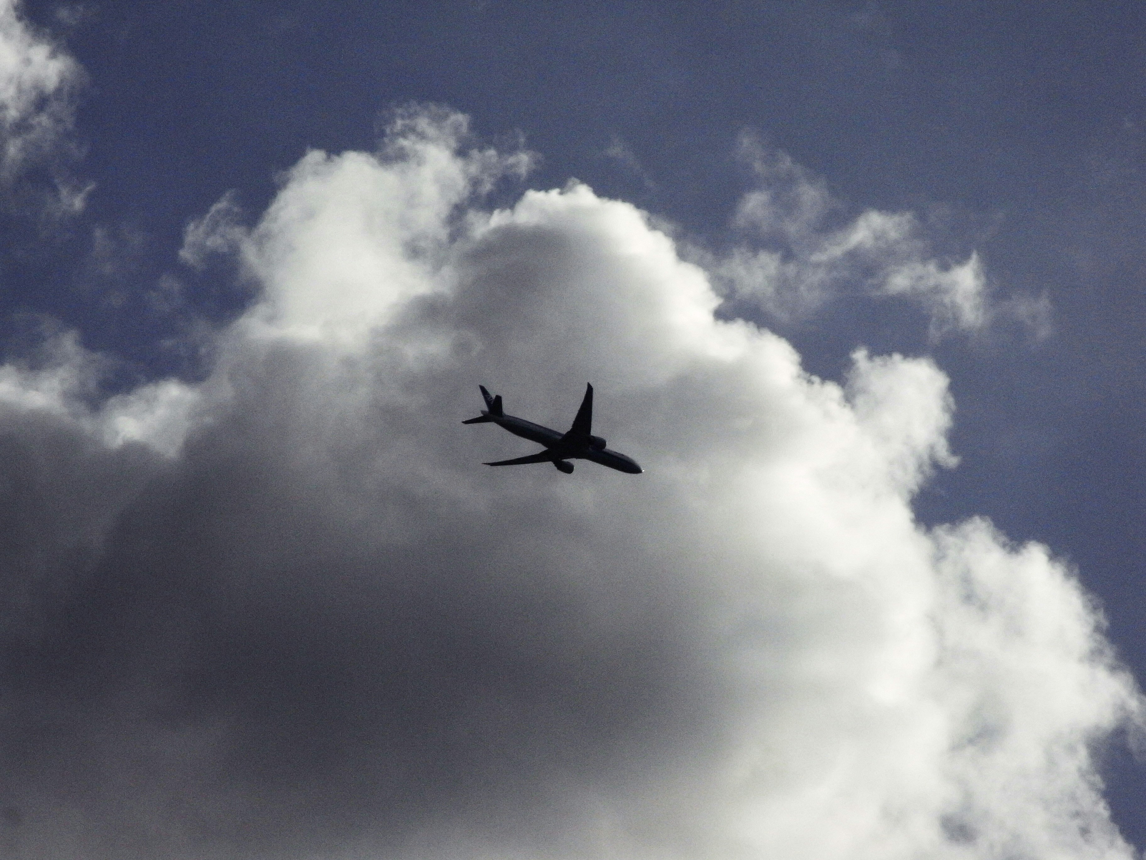 Airplane navigating through a dramatic sky filled with billowing clouds.