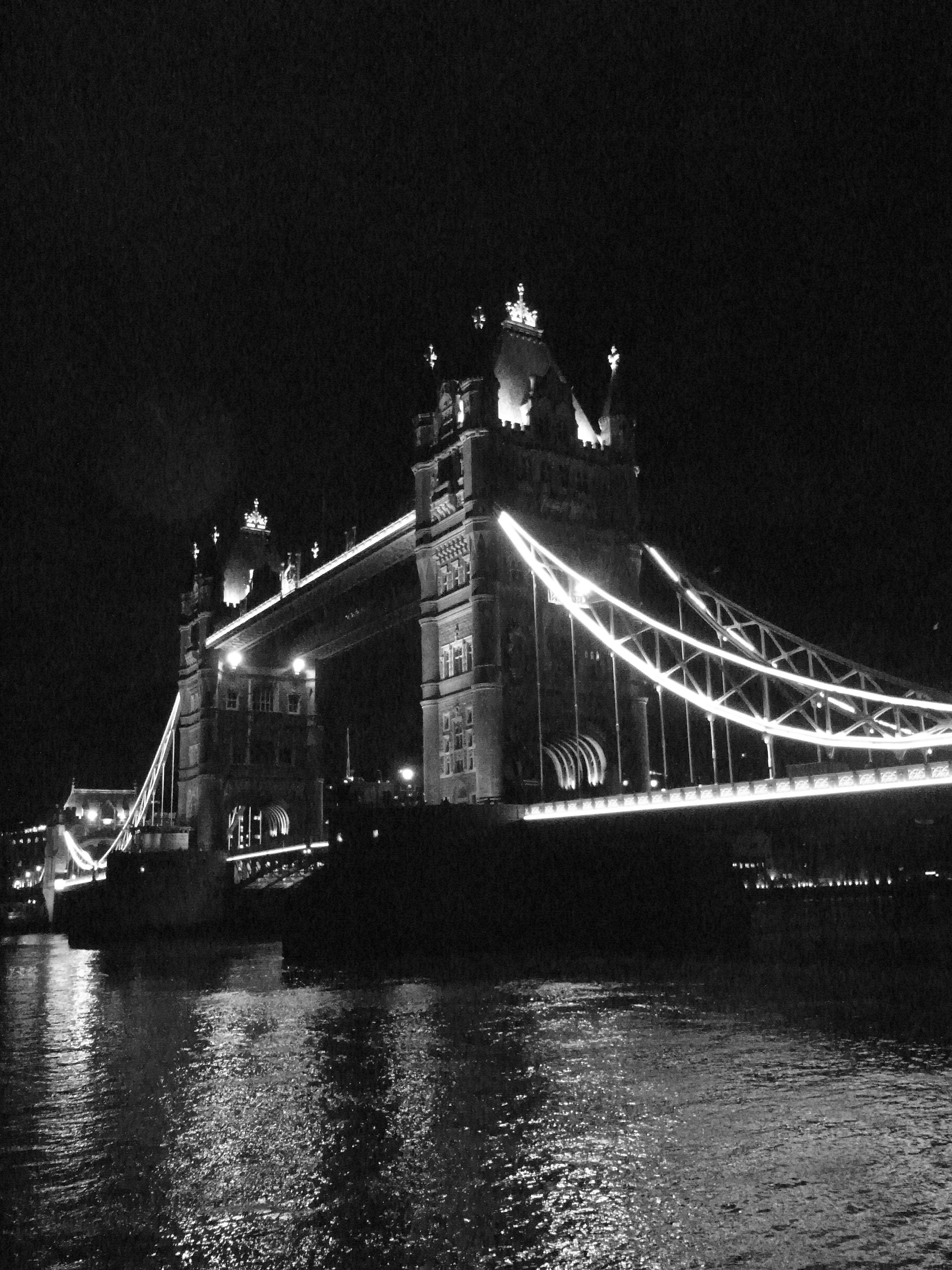Tower Bridge illuminated against the night sky, showcasing its architectural beauty and reflections on the water below.