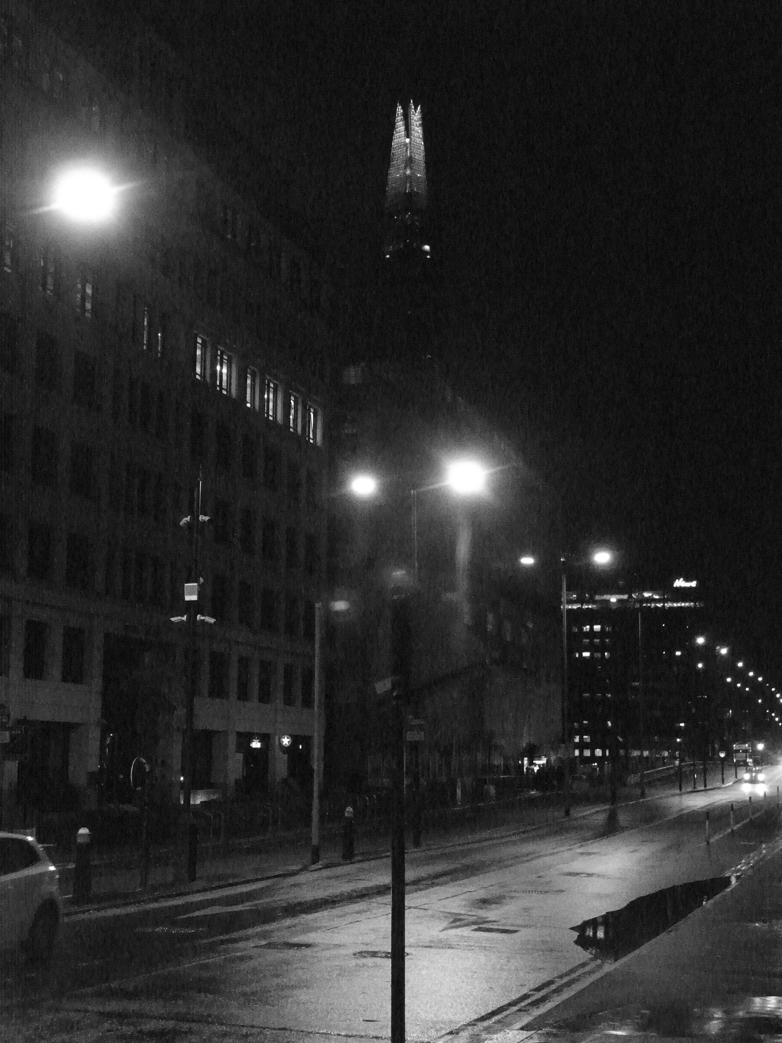 City street at night with illuminated buildings and lights.