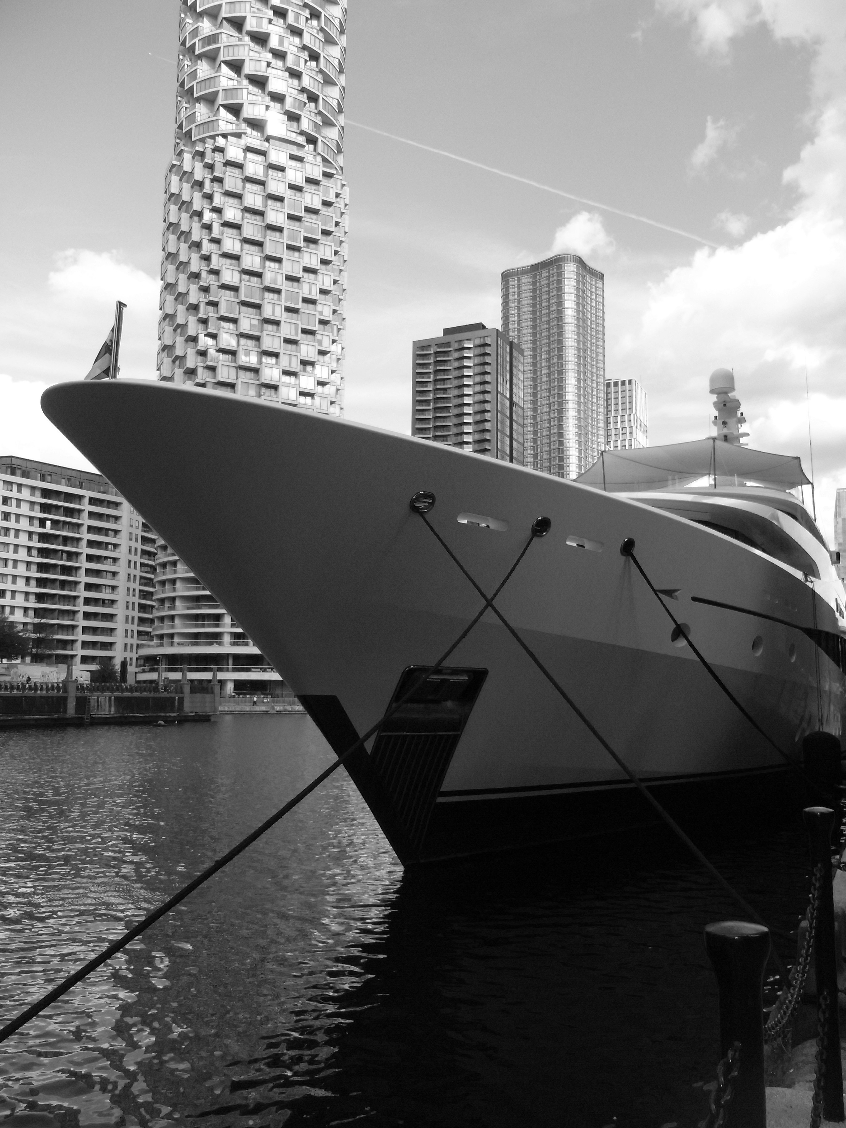 Luxury yacht docked alongside modern skyscrapers, showcasing a blend of nautical design and urban architecture.