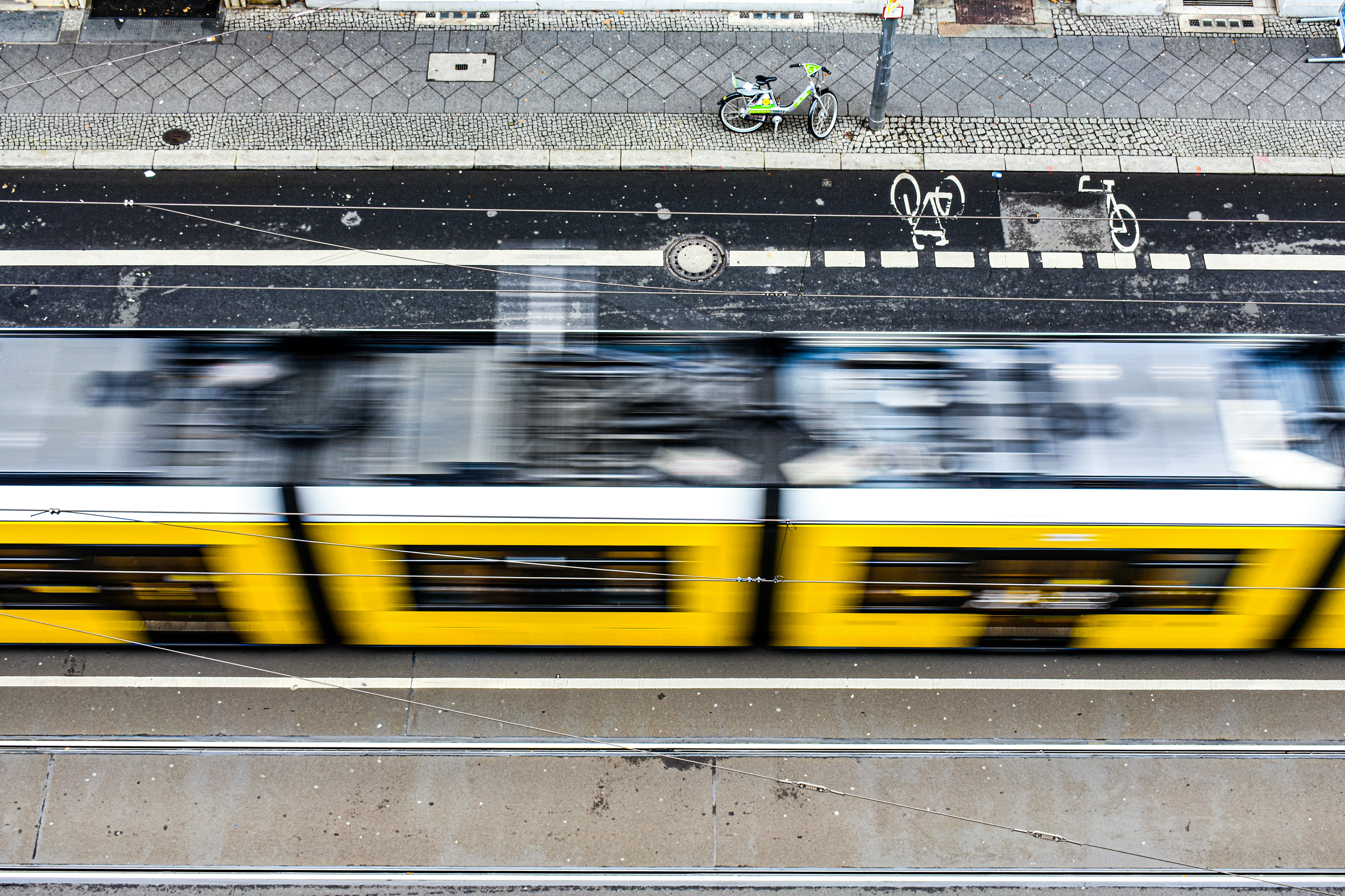 A tram is moving through a street with bike lanes | Yellow tram blurred by motion on tracks