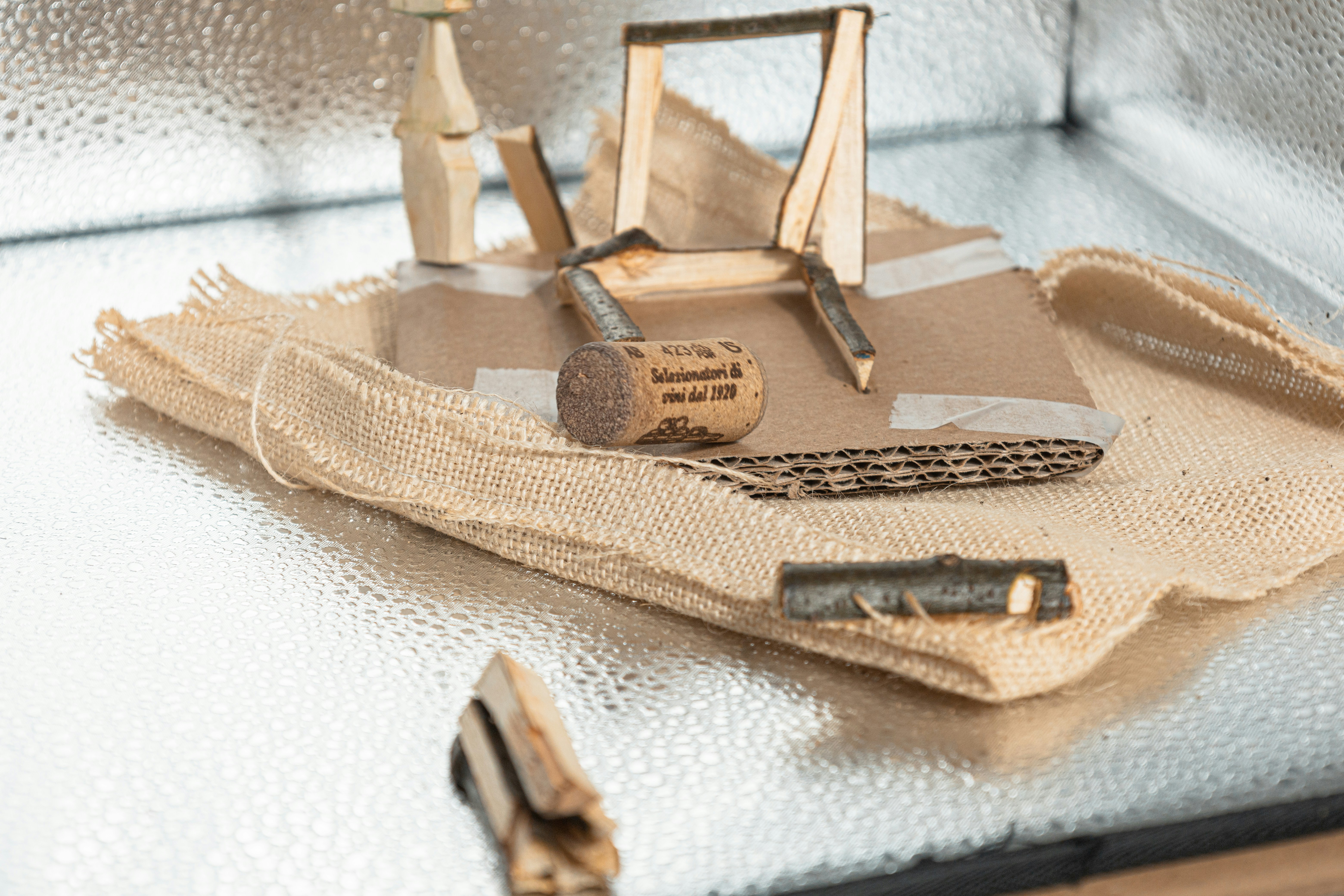 An artistic arrangement of natural materials, including wood and burlap, set against a reflective surface, showcasing creative design elements.