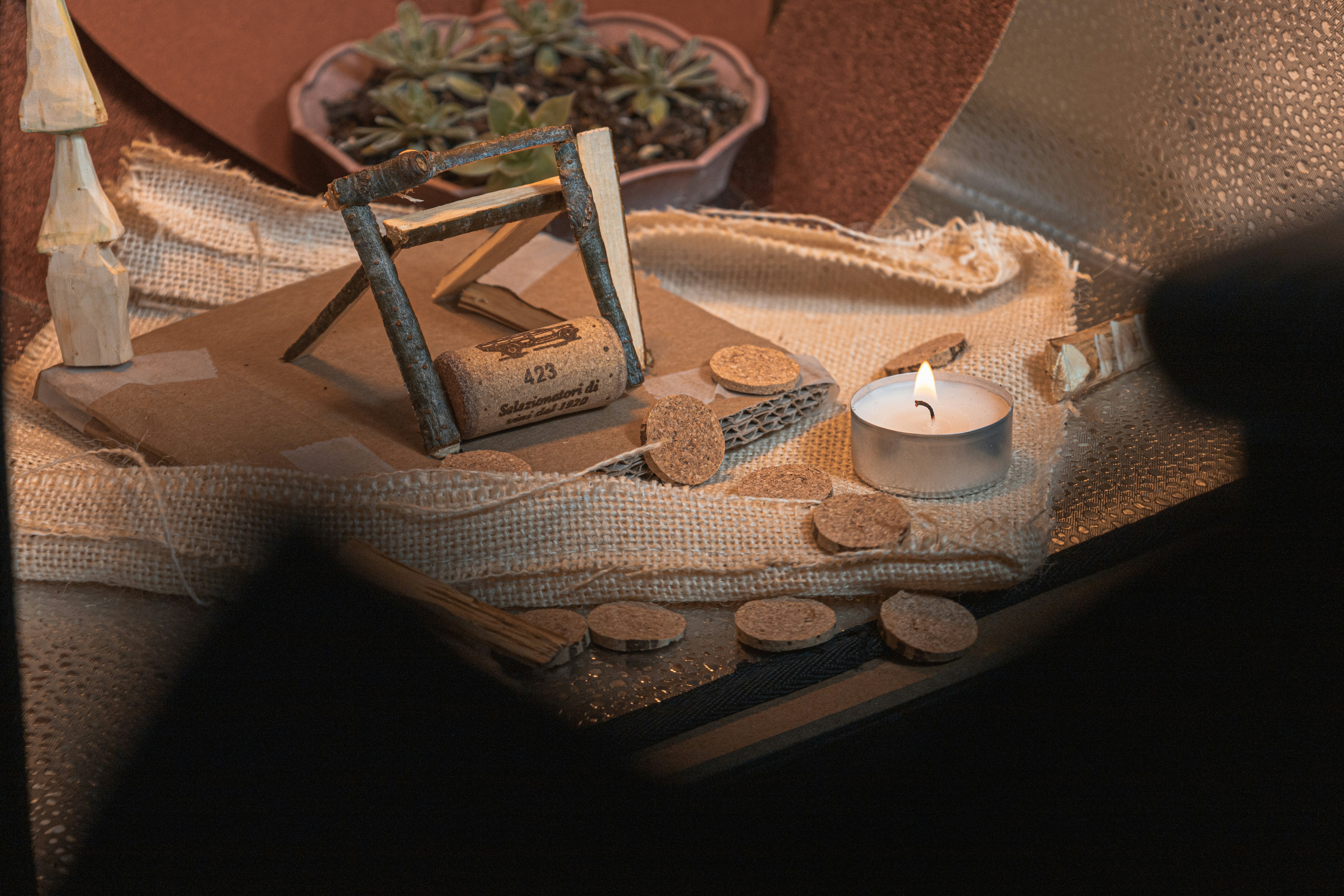 Hourglass and lit candle on rustic table setting.