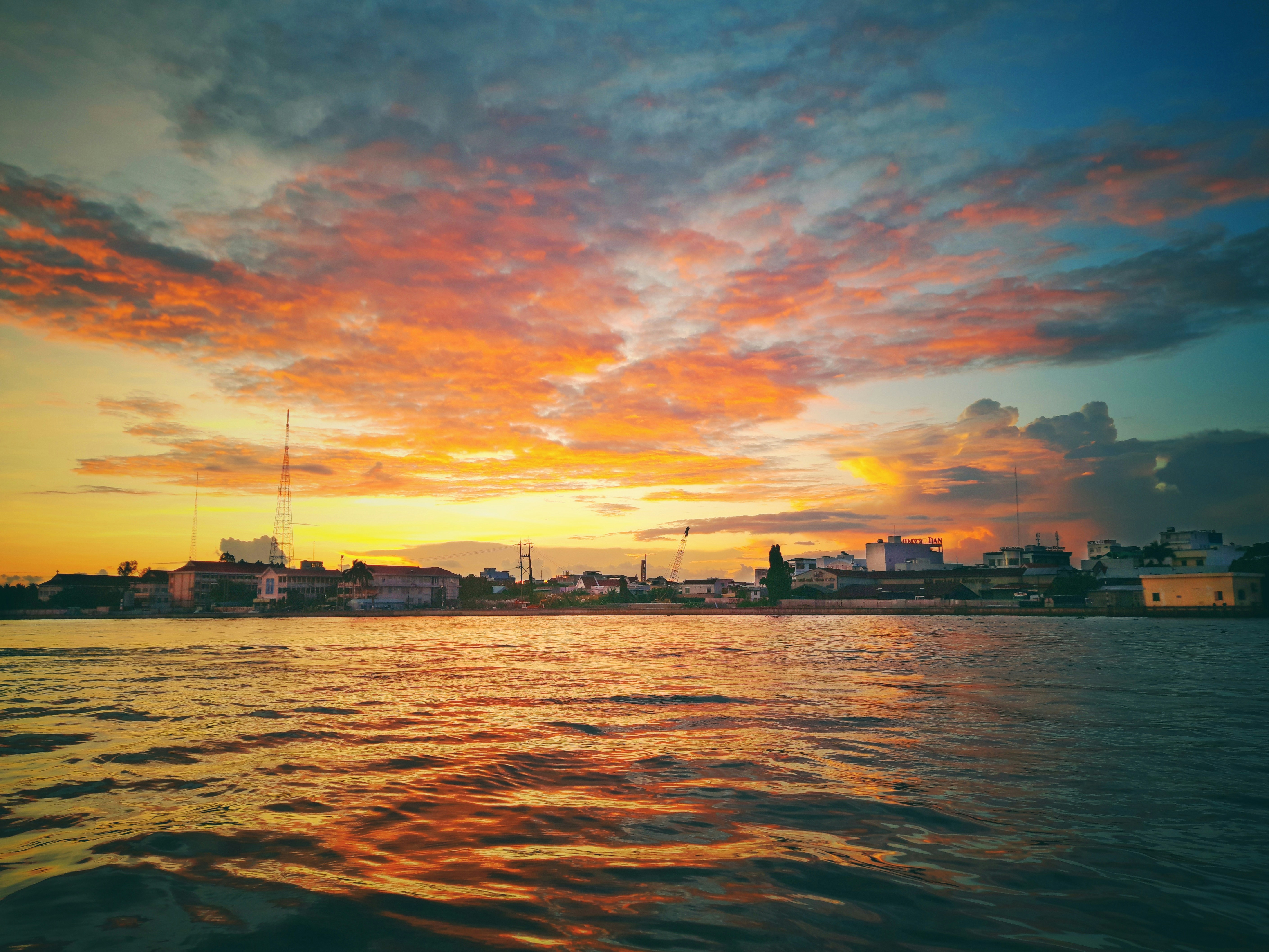 Vibrant sunset over a calm river and city skyline
