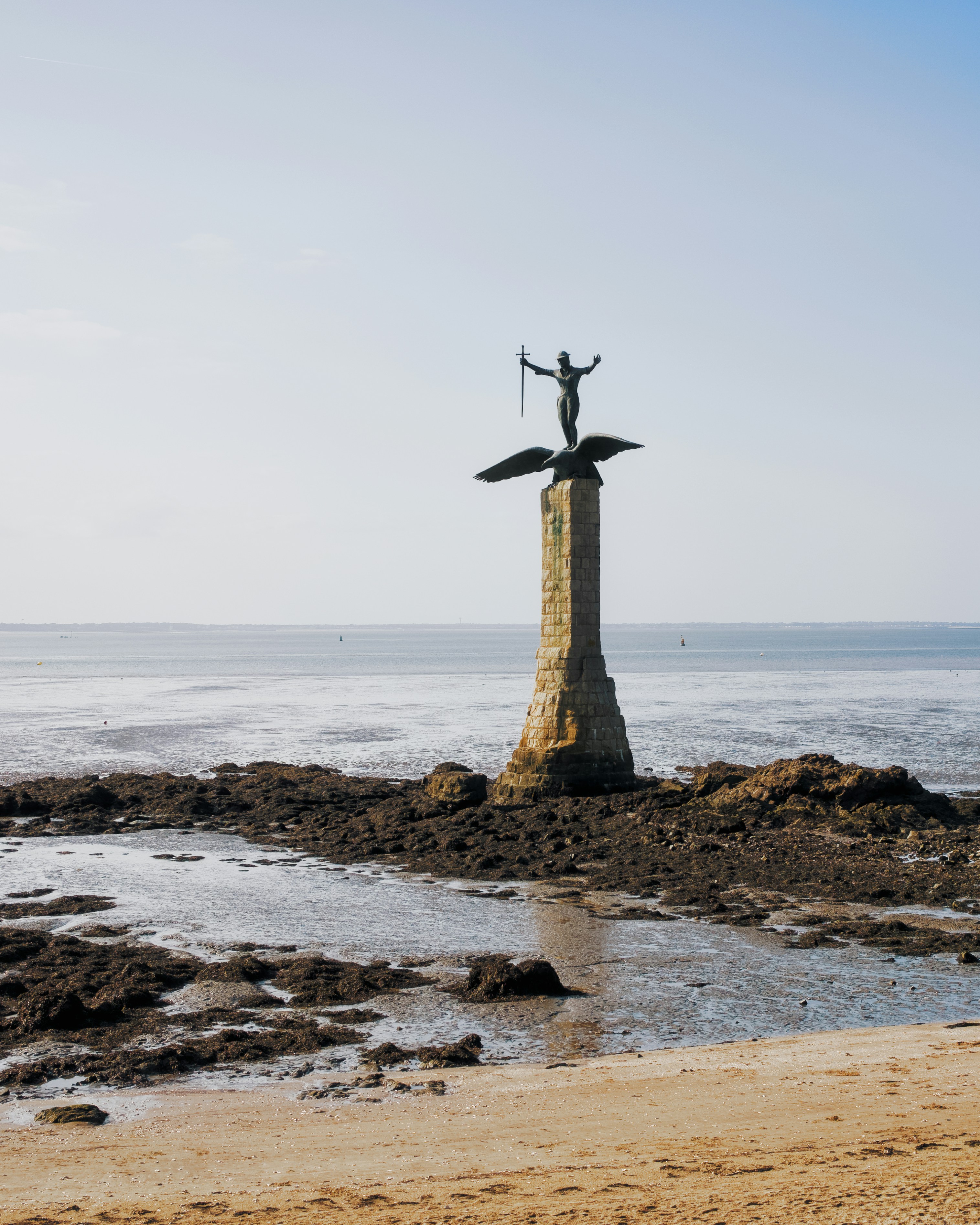 Stone Sentinel on a Seaside Pillar at Low Tide