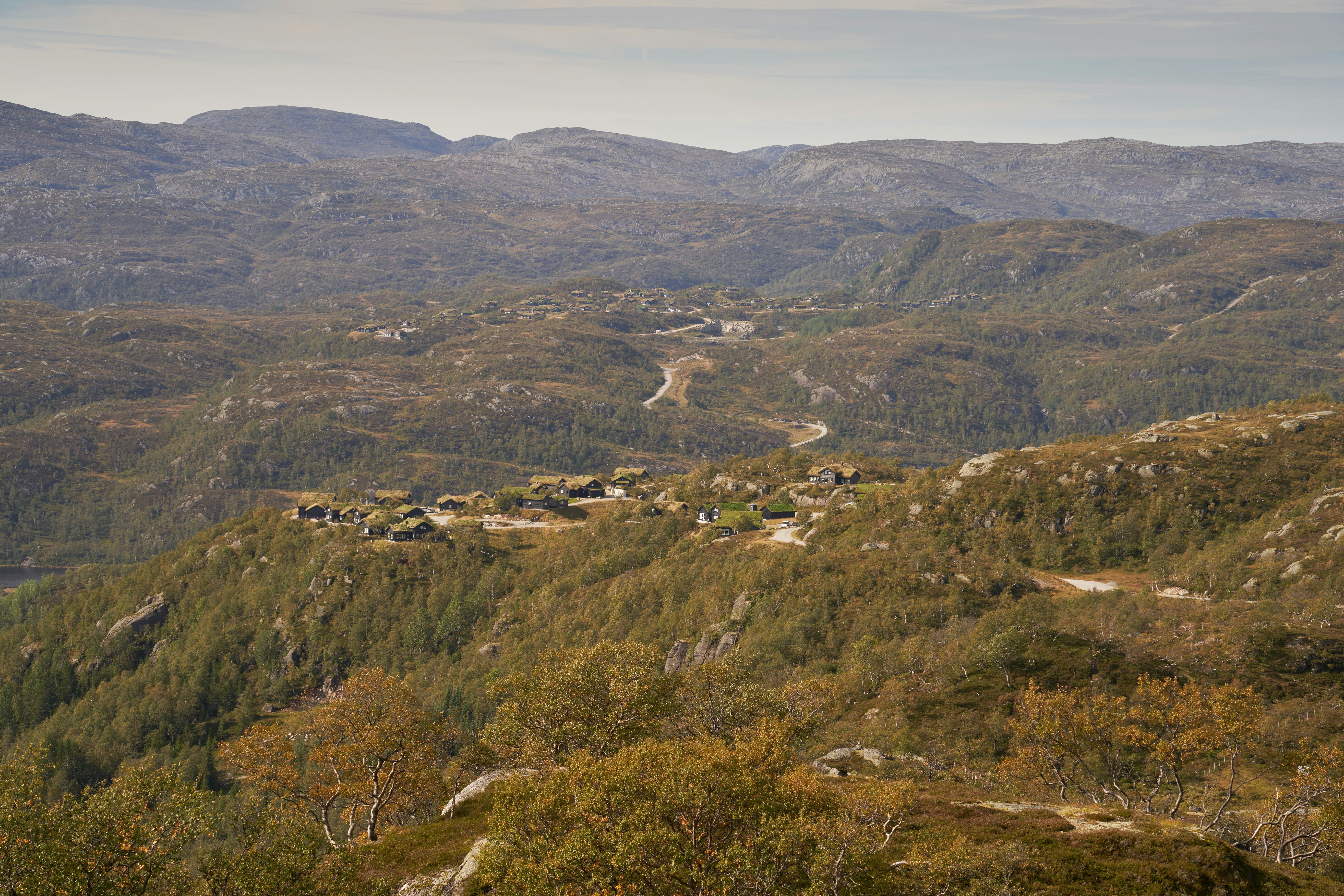 A group of cabins in the Norwegian highland during the summer, near to Suleskard | Mountainous landscape with sparse trees and rocks.