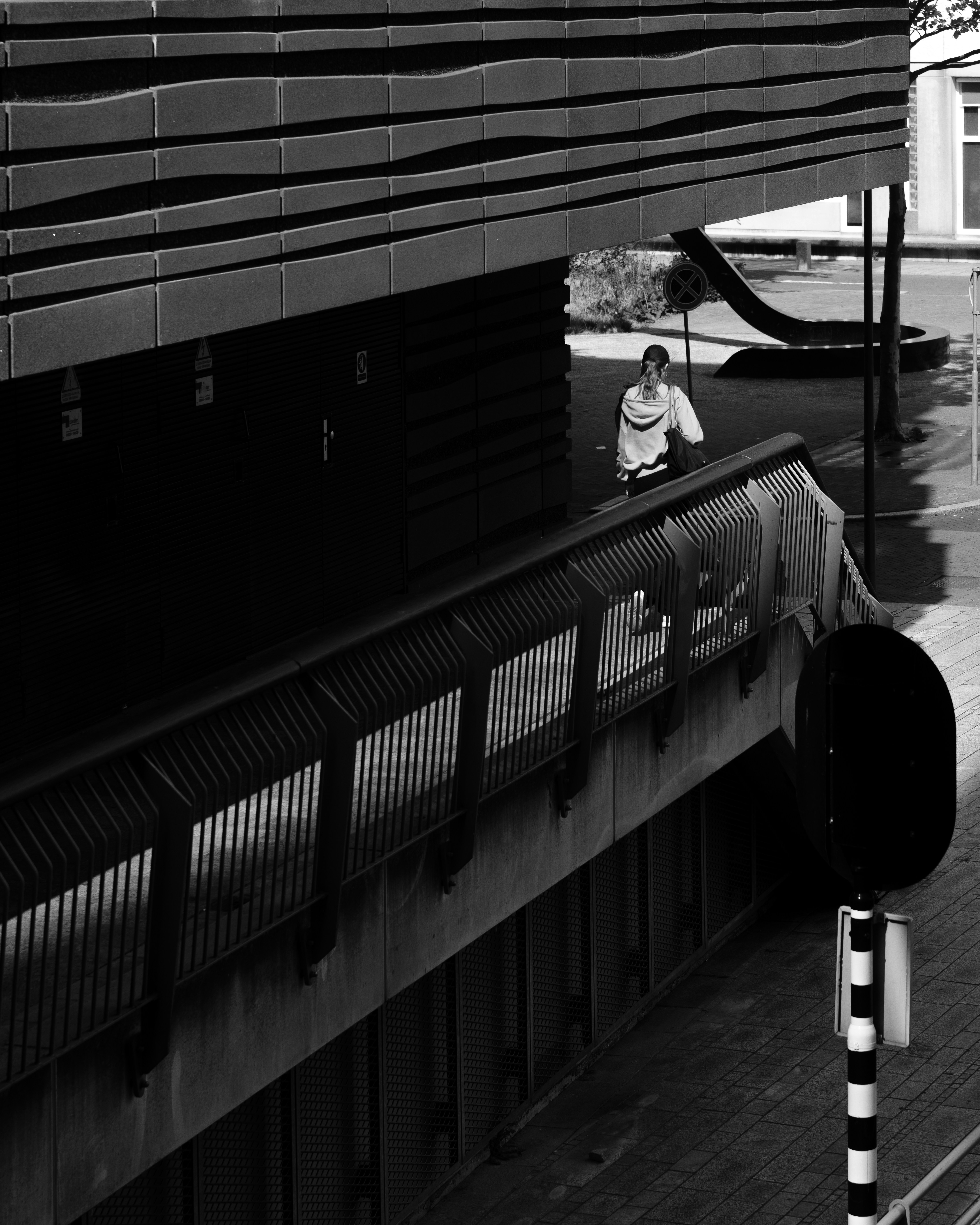Silent Geometry: A lone passerby on a diagonal of steel and shade