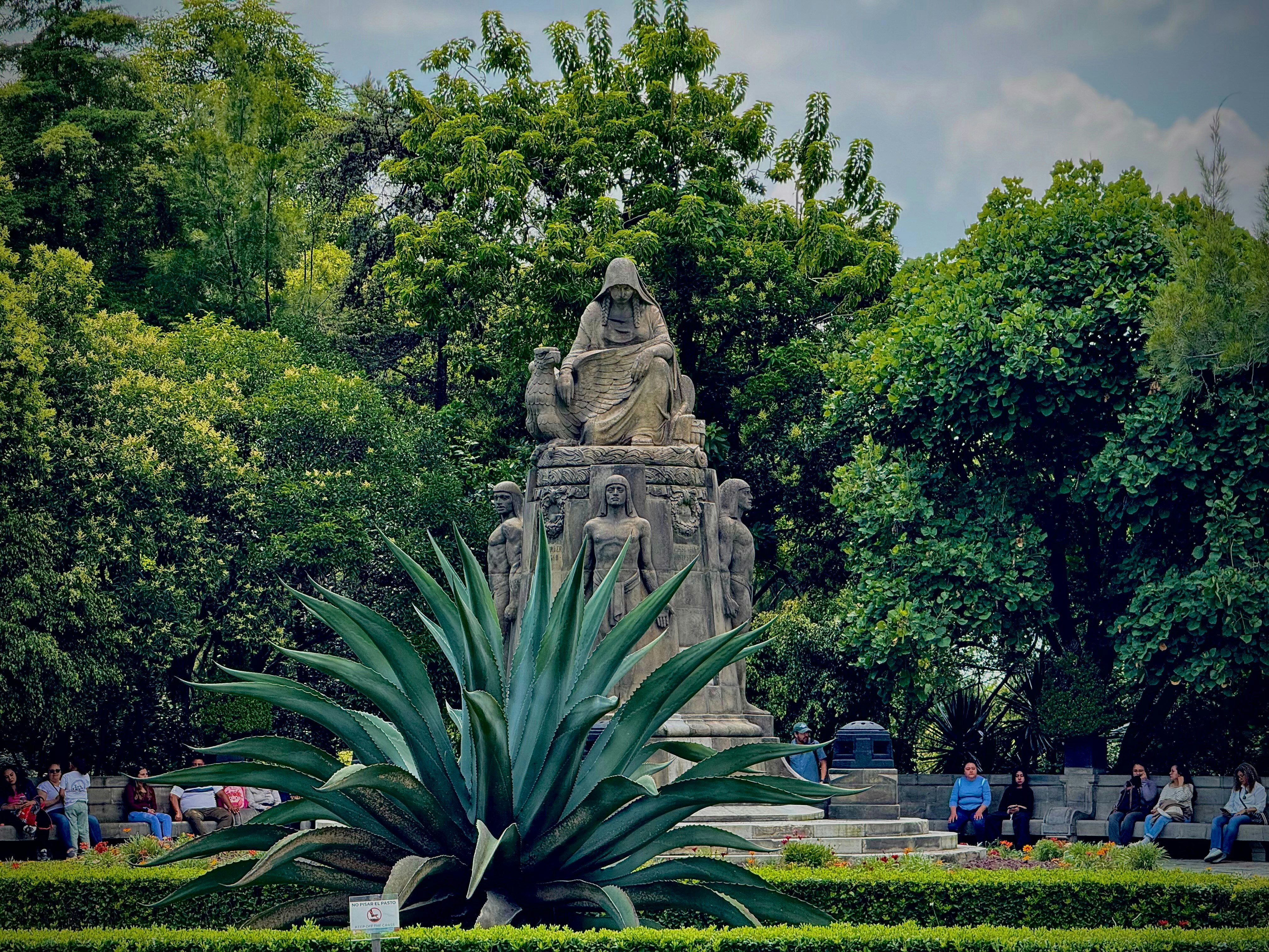 Stone monument surrounded by lush green trees and plants.