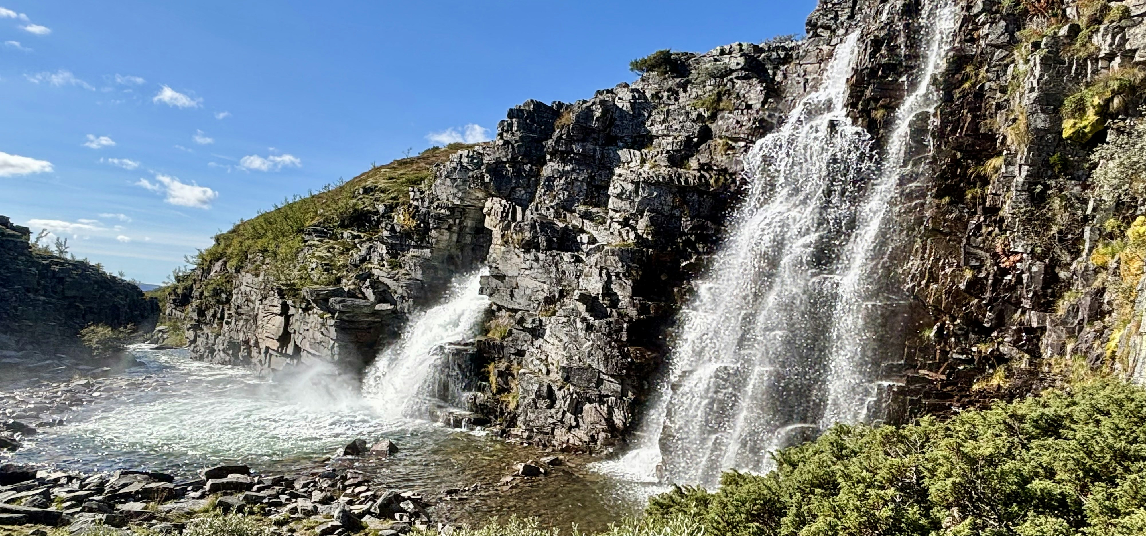 Storulfossen in Rondane september 2025! | Multiple waterfalls cascade down rocky cliffs under a blue sky.