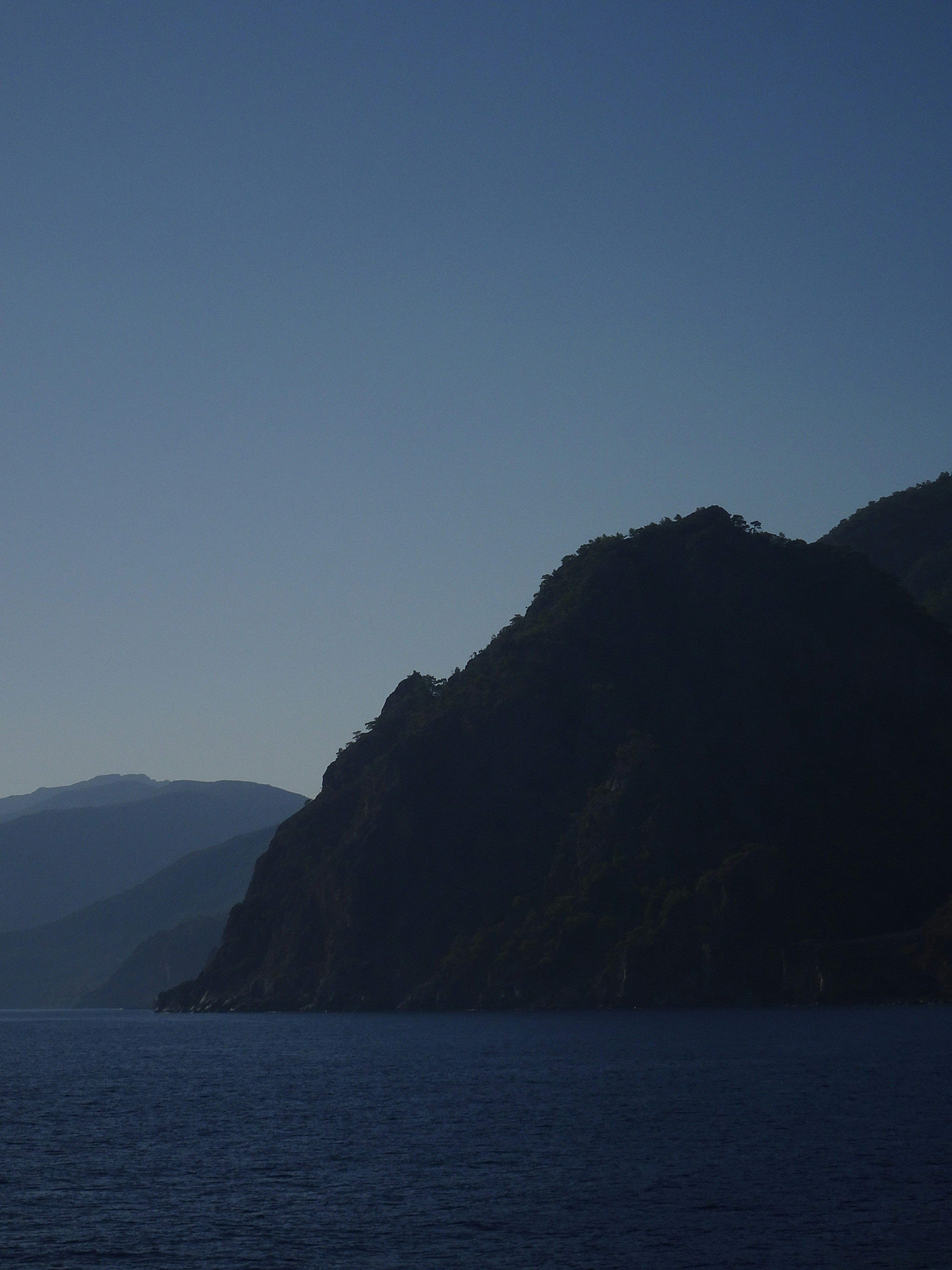 **light wind and the smell of the sea** | Dark mountains rise from the deep blue sea.