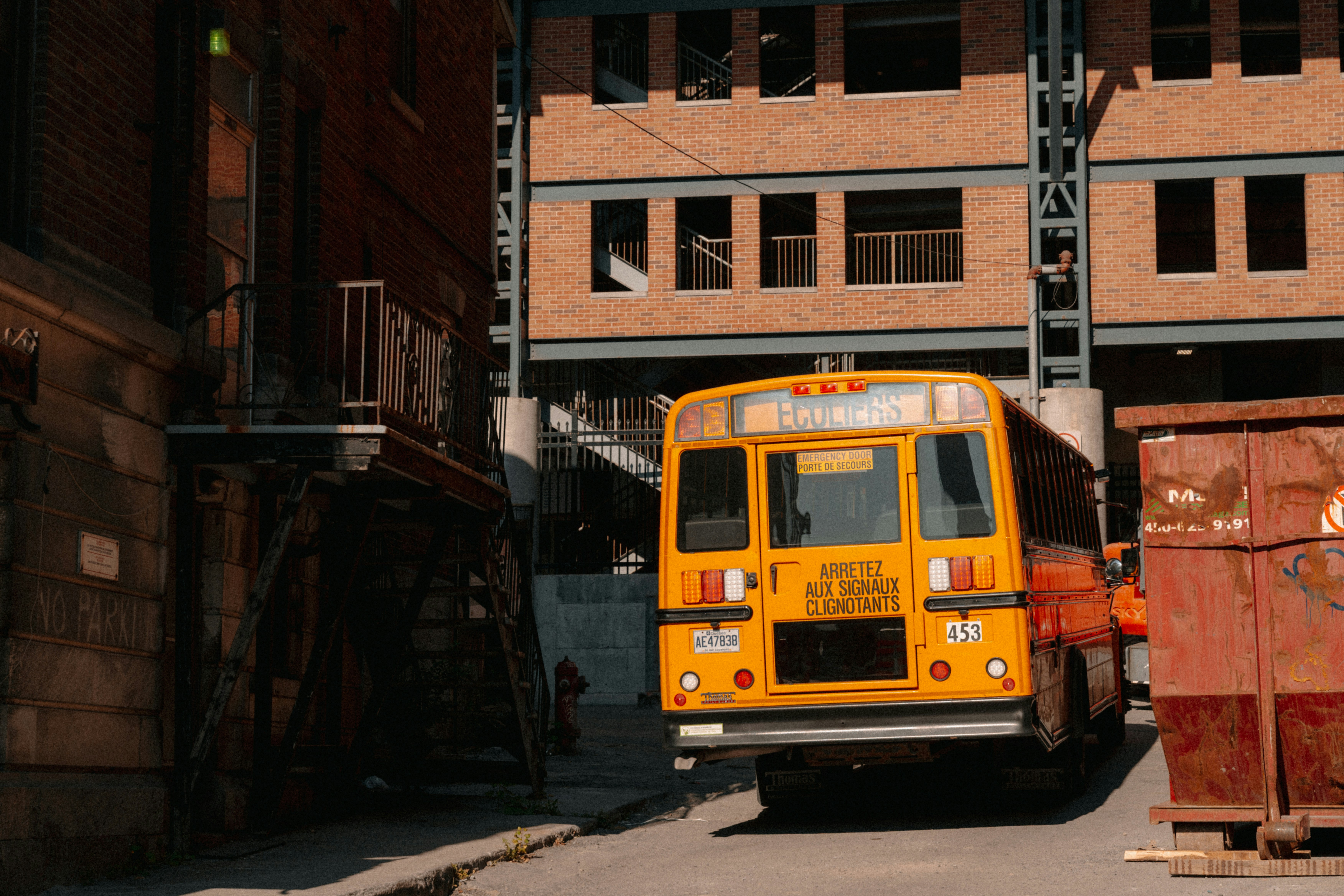 Yellow school bus turning down an alleyway.