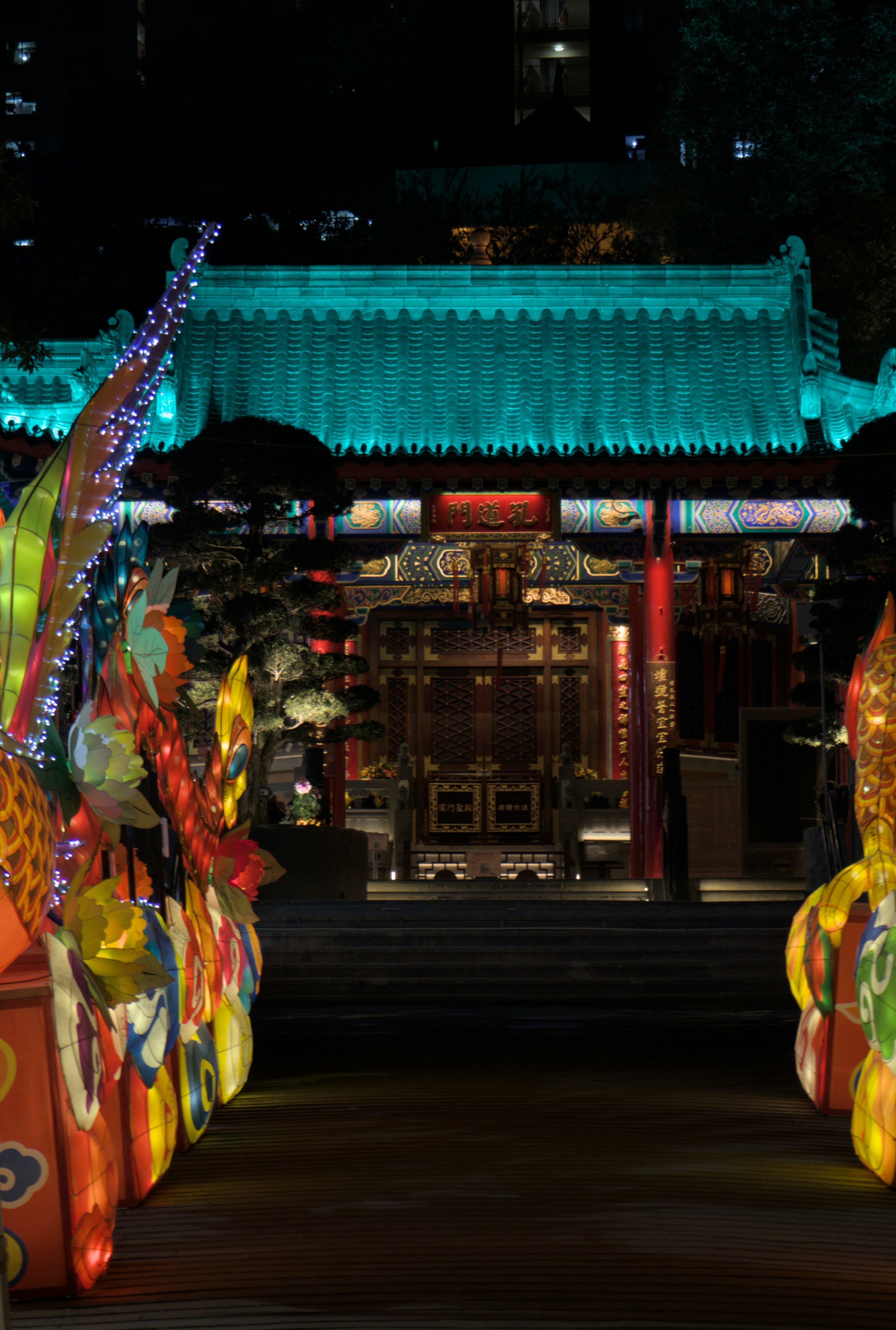 Vibrantly colored lanterns lead to a beautifully adorned traditional building, showcasing intricate designs and festive lighting.
