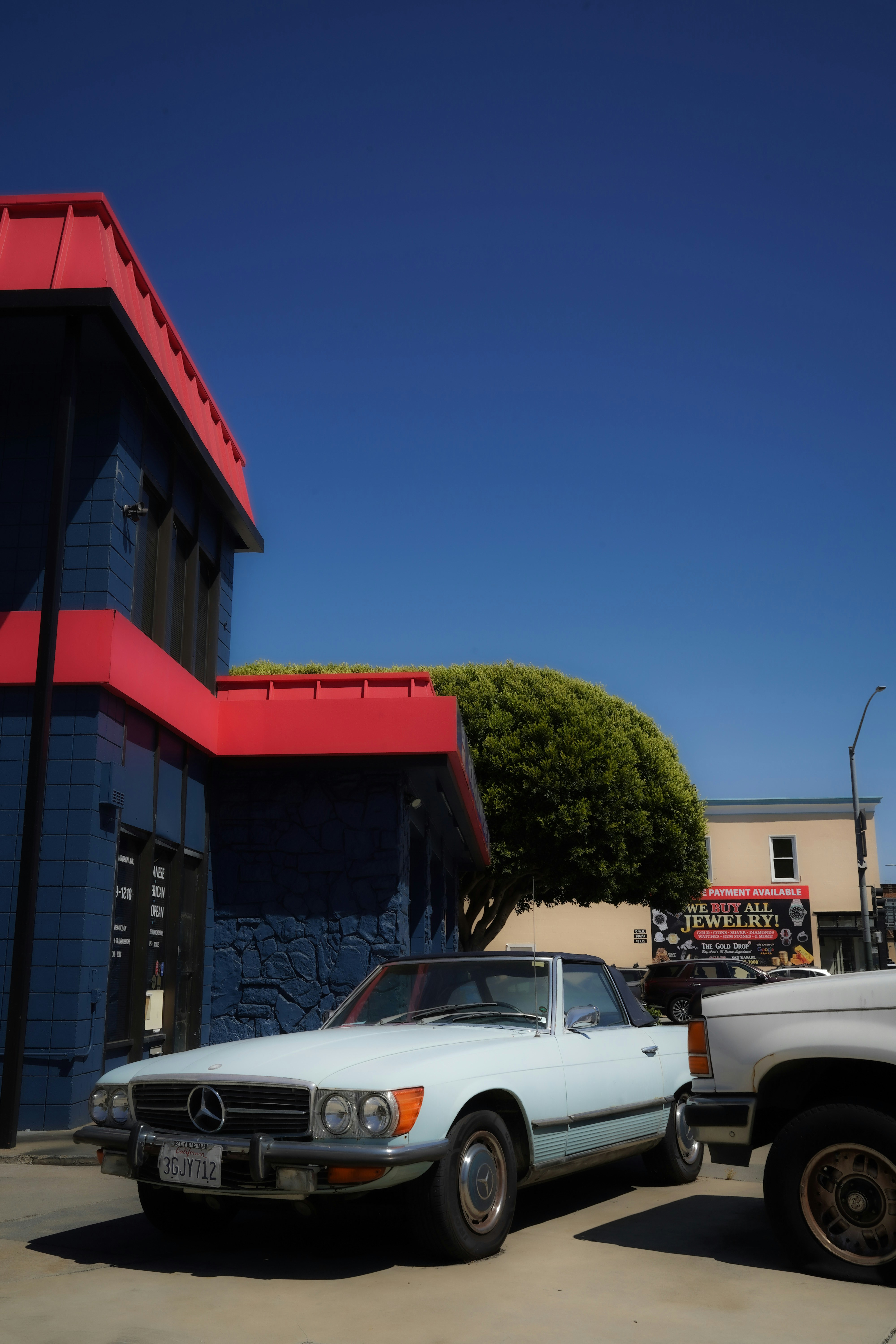 Light blue vintage car parked outside blue building