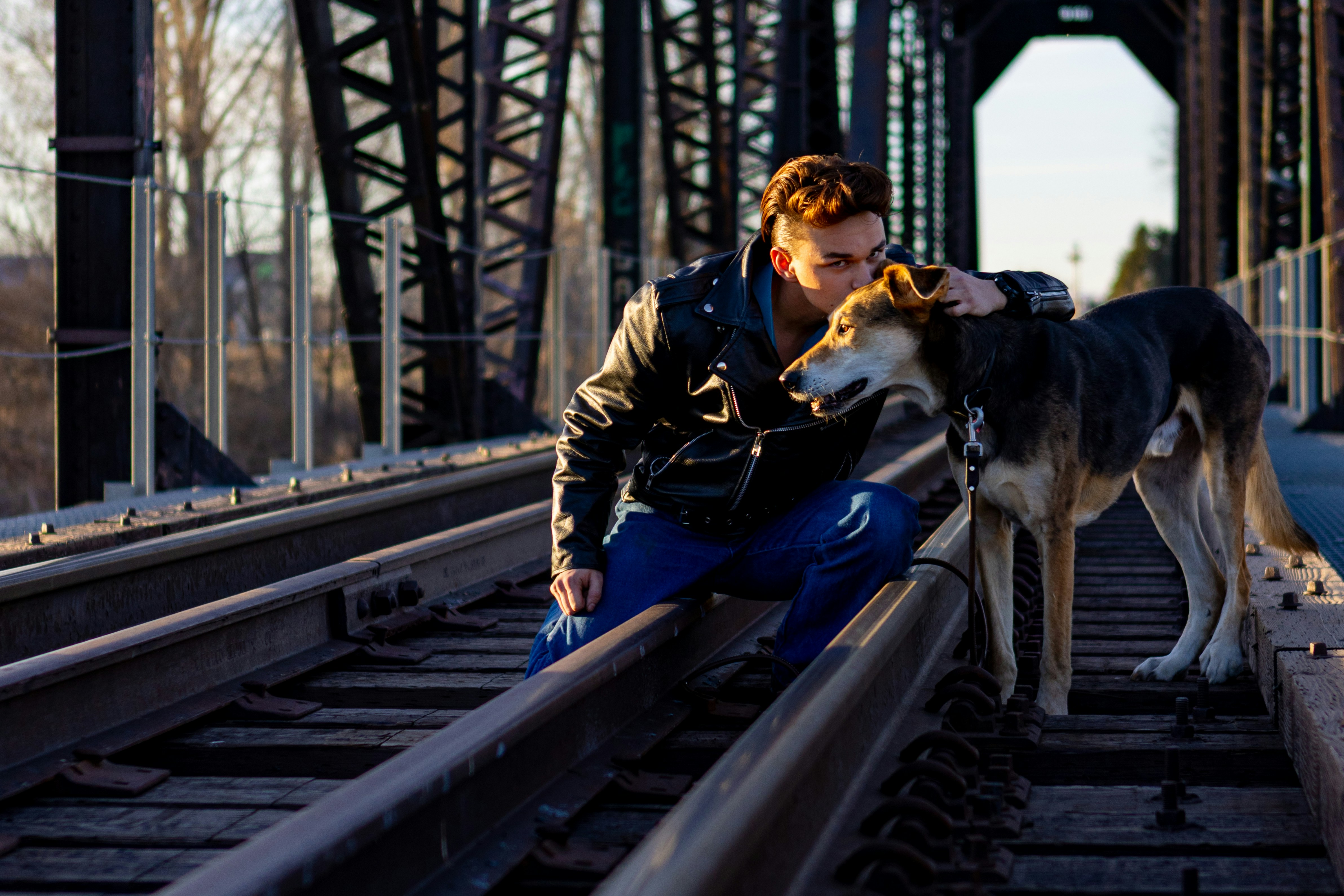 Railside Moment: A Man and Husky Share a Gentle Kiss Under Golden Steel