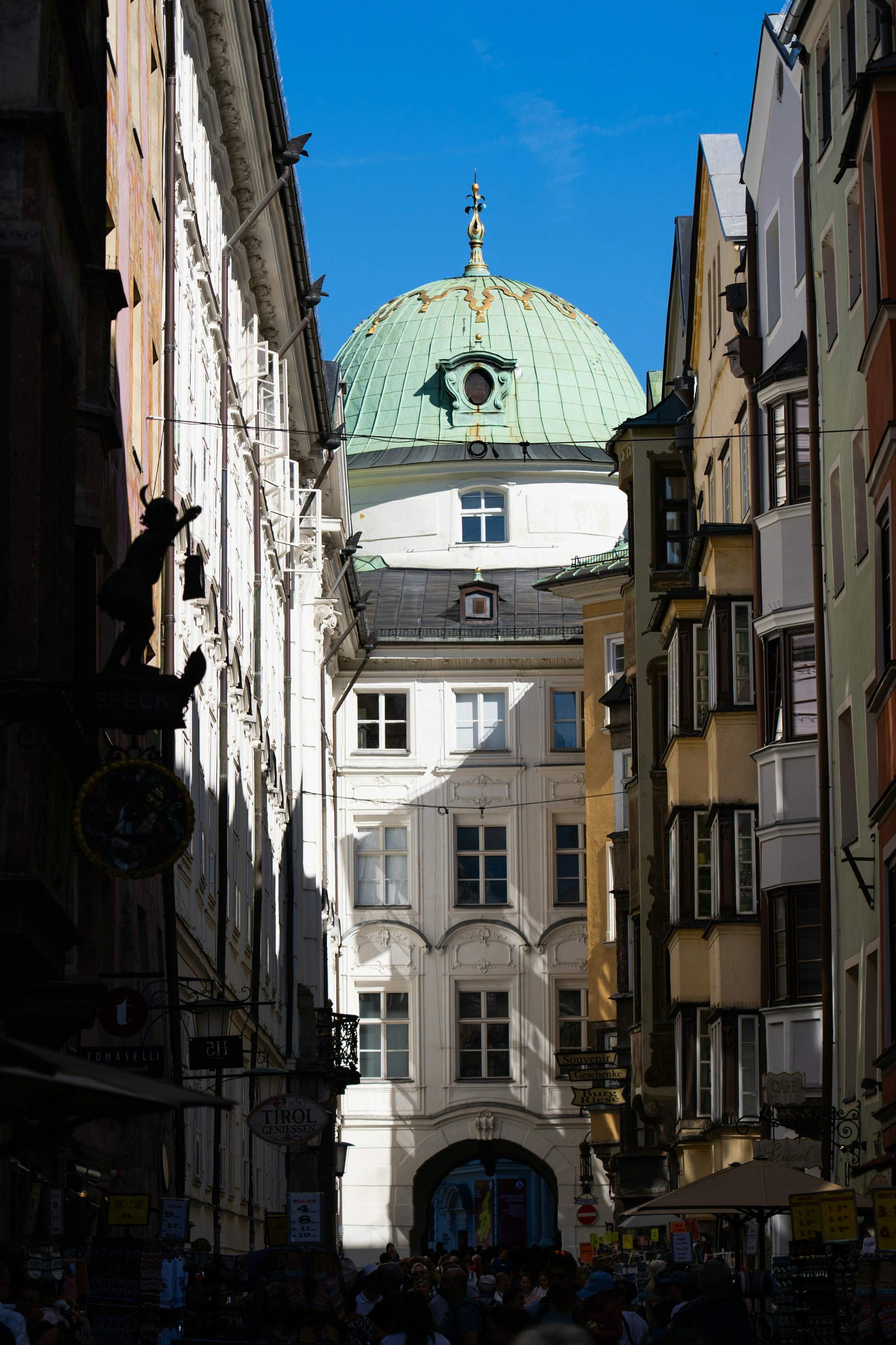 Historic building with a green dome framed by narrow streets, showcasing intricate architecture and vibrant colors.