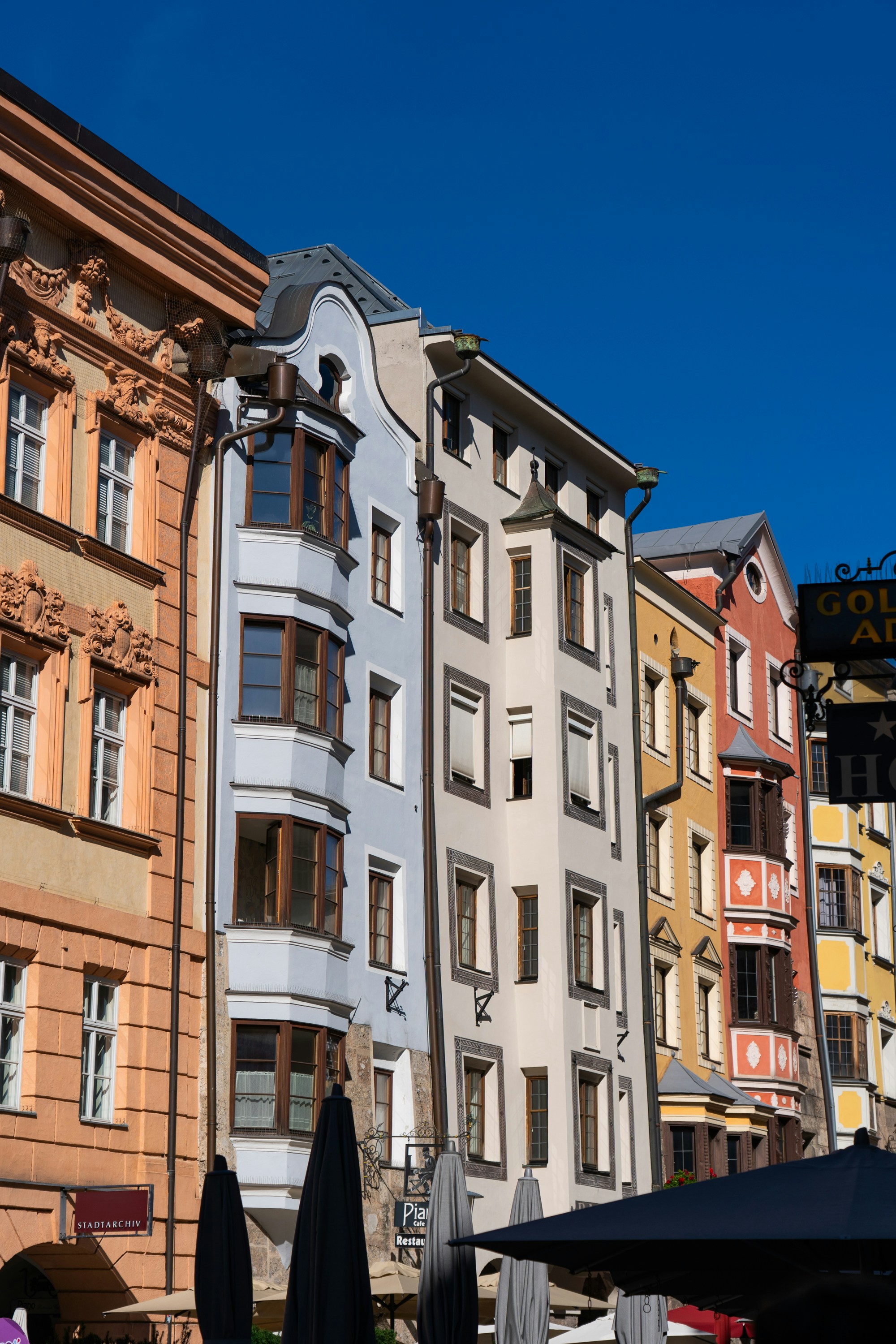 Charming buildings with intricate details and vibrant colors lining a street under a clear blue sky.