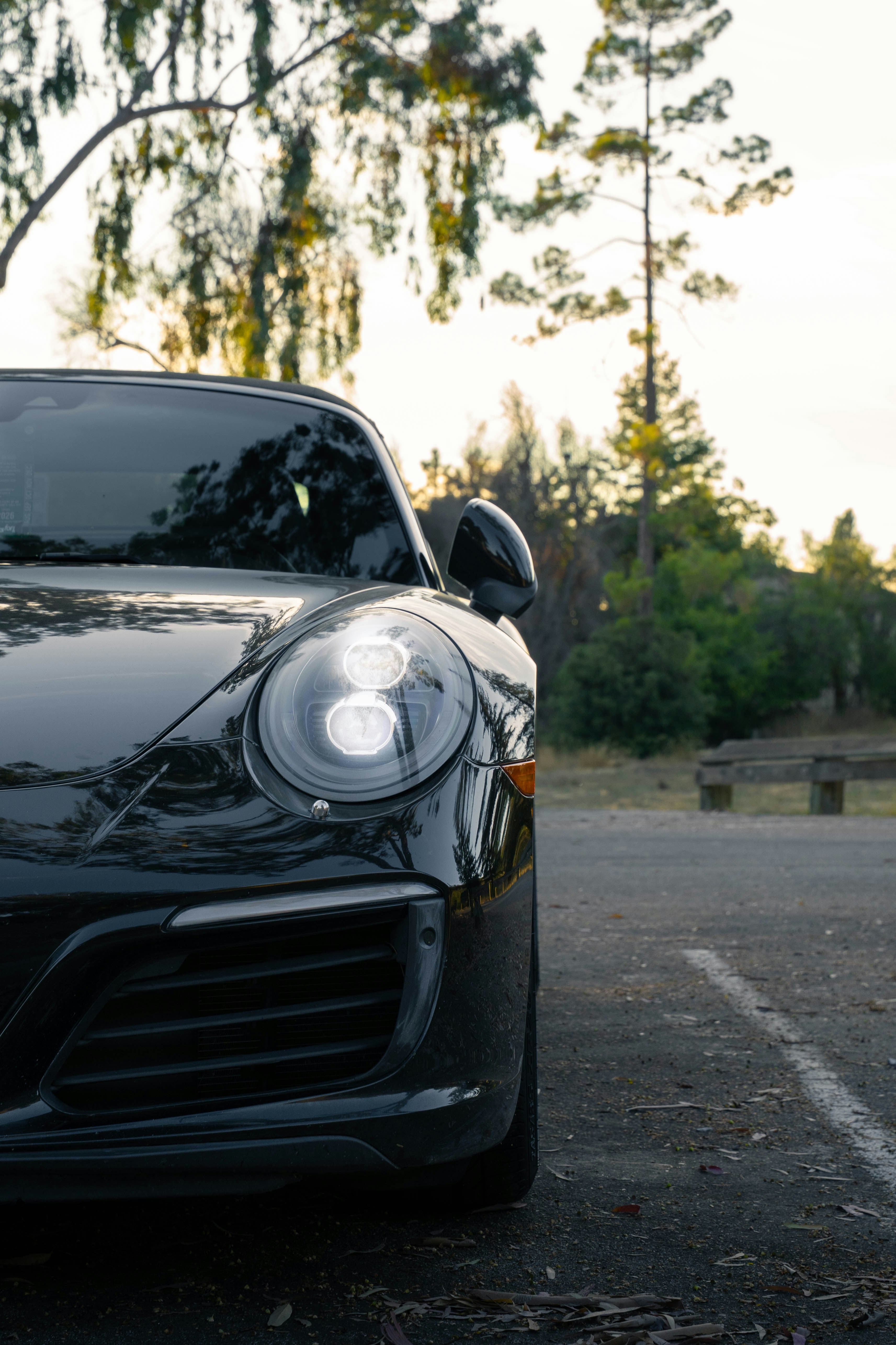 Black sports car parked outdoors at sunset.