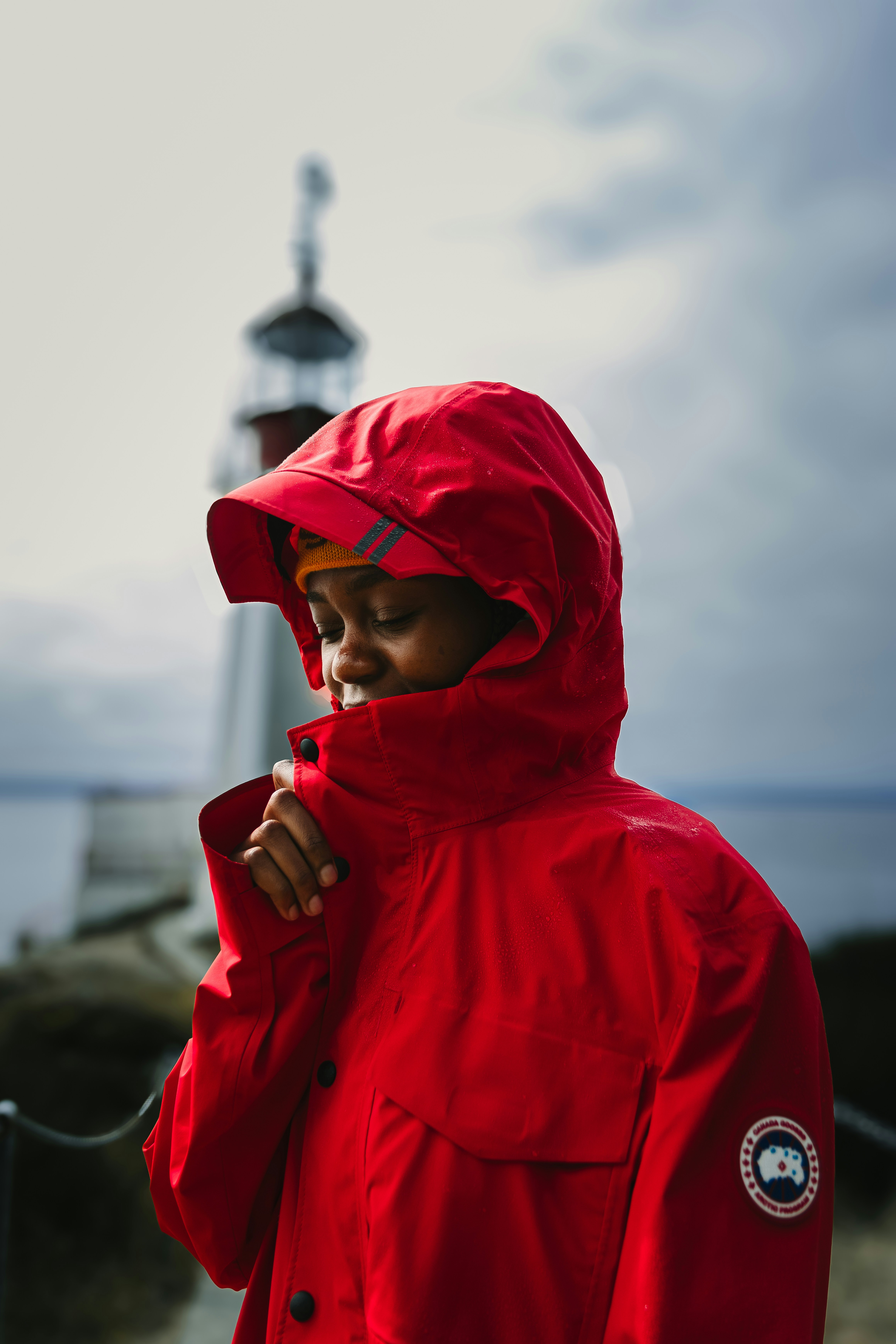 Crimson Hood at the Edge of the Sea: Quiet Portrait by the Lighthouse