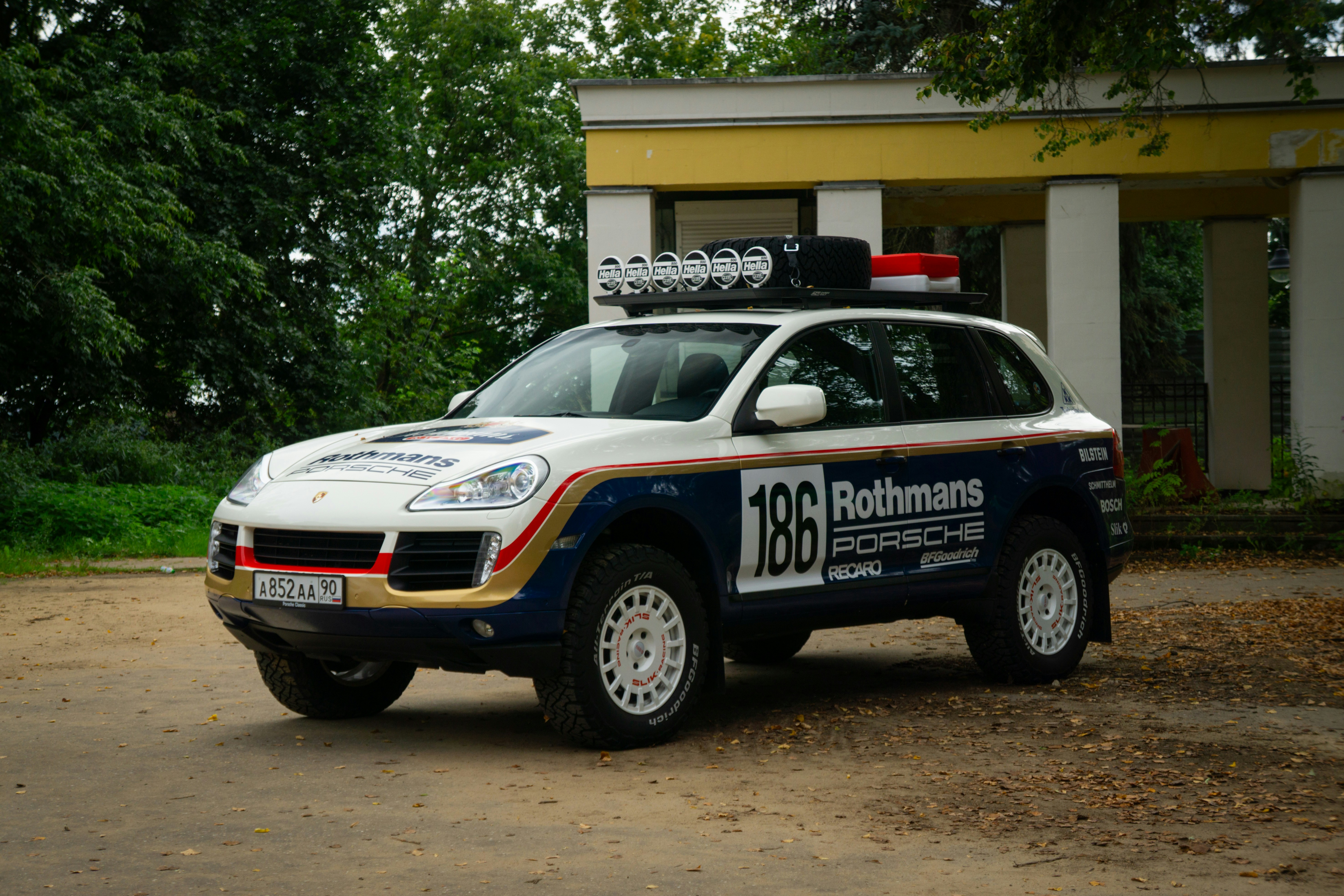 Rally car with rothmans livery parked outside building