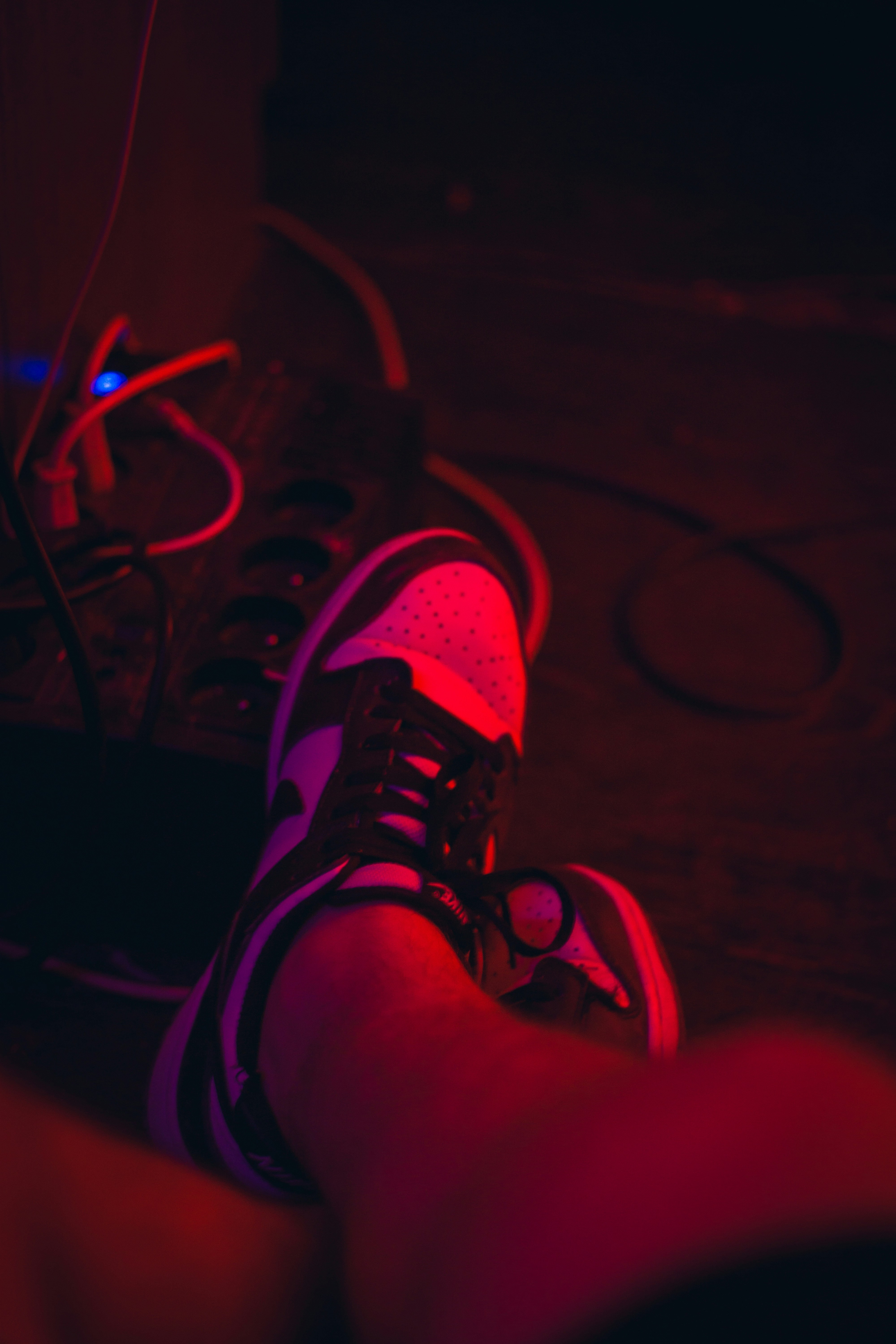 A sneaker on a pedalboard with red lighting.