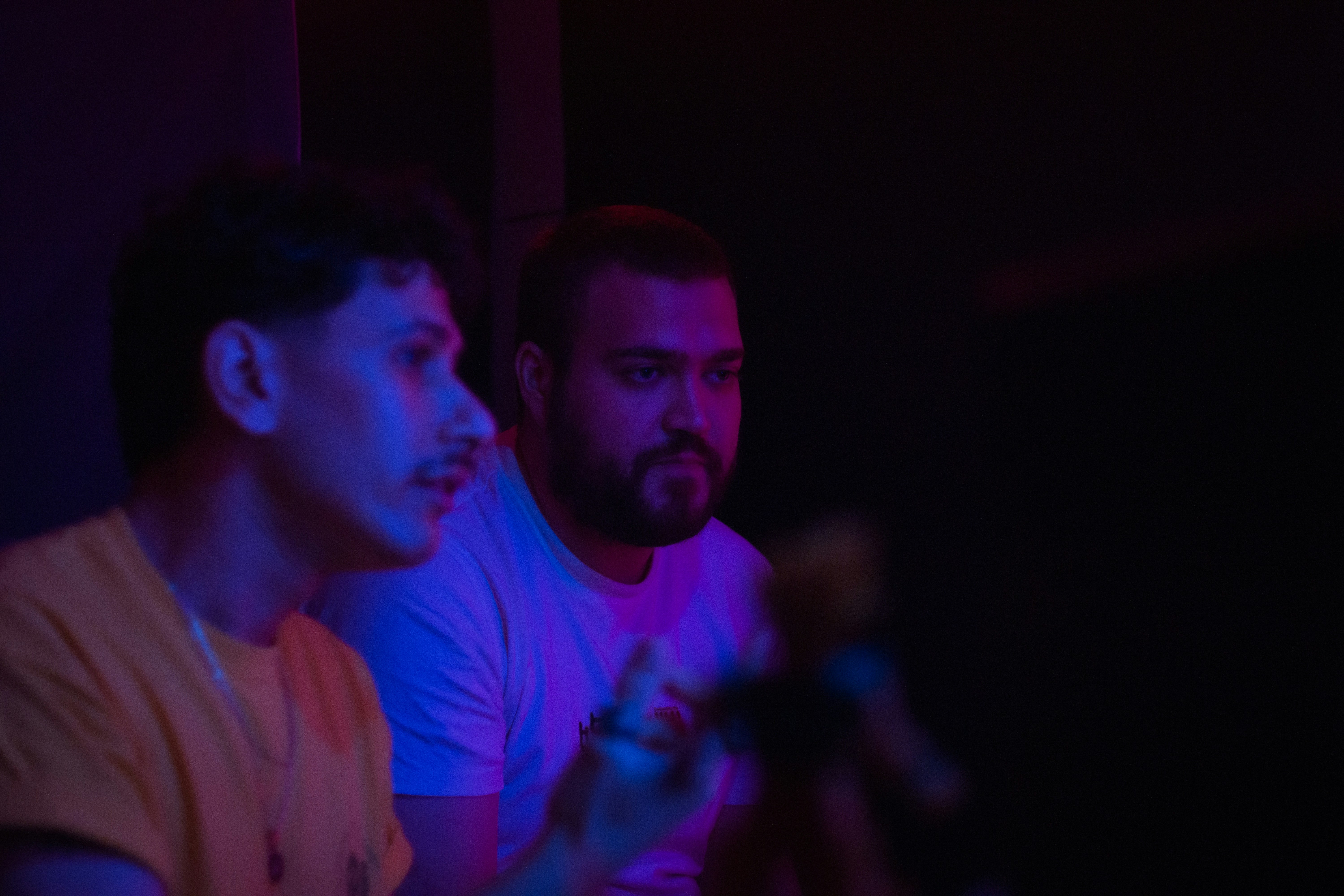 Two men illuminated by neon lights in darkness