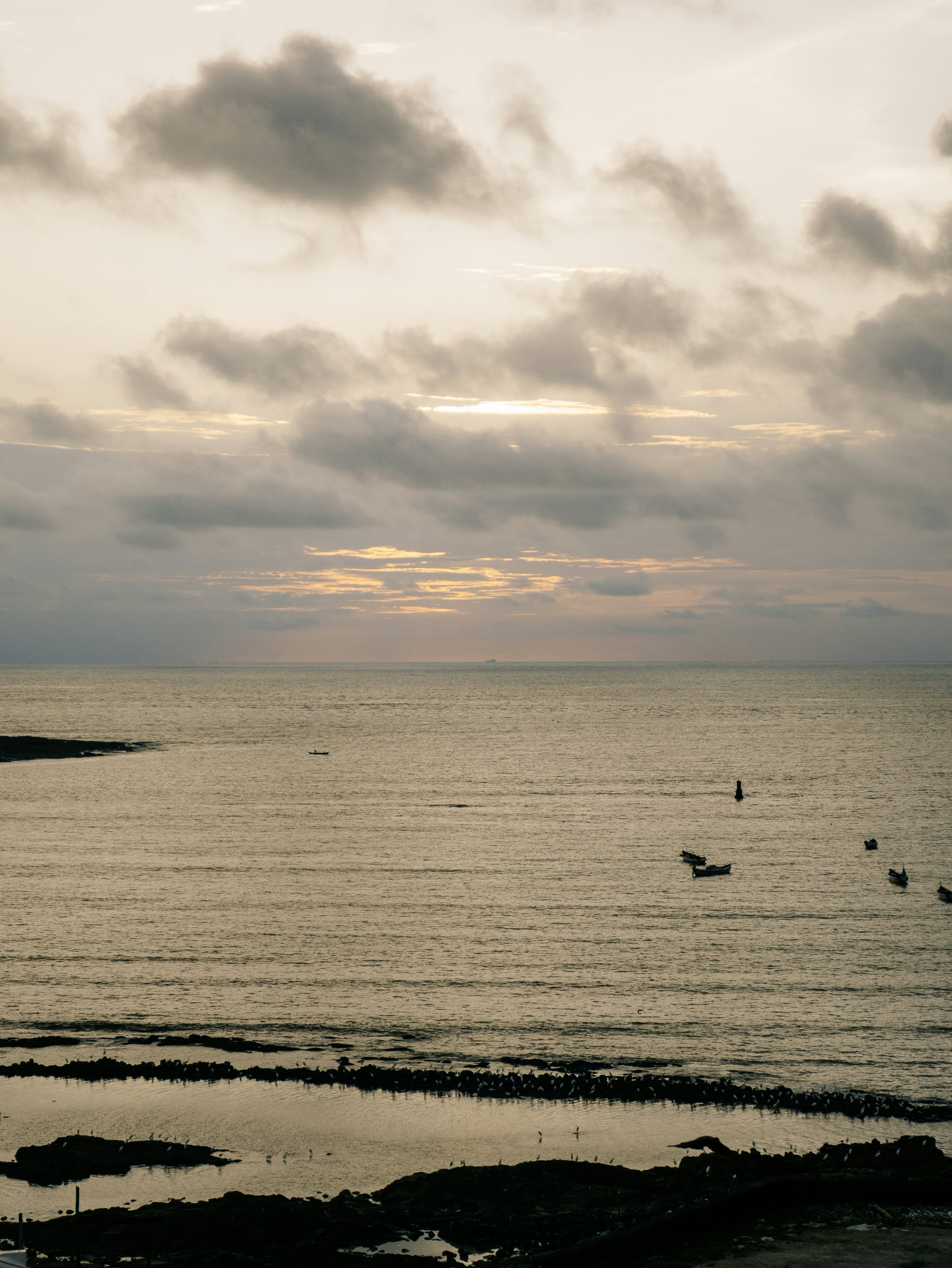 Boats on the ocean under a cloudy sky