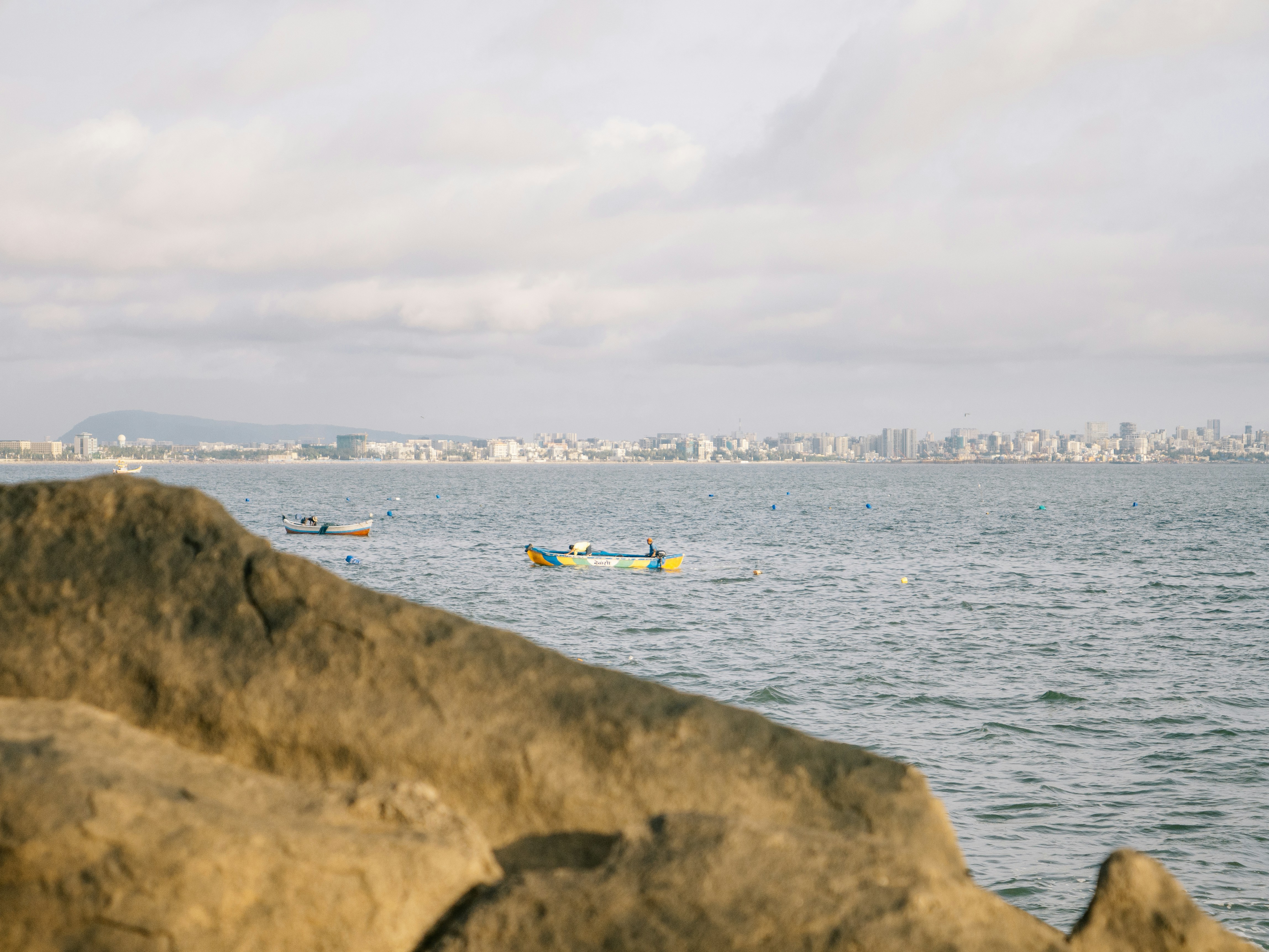 Small boats on the ocean with city skyline