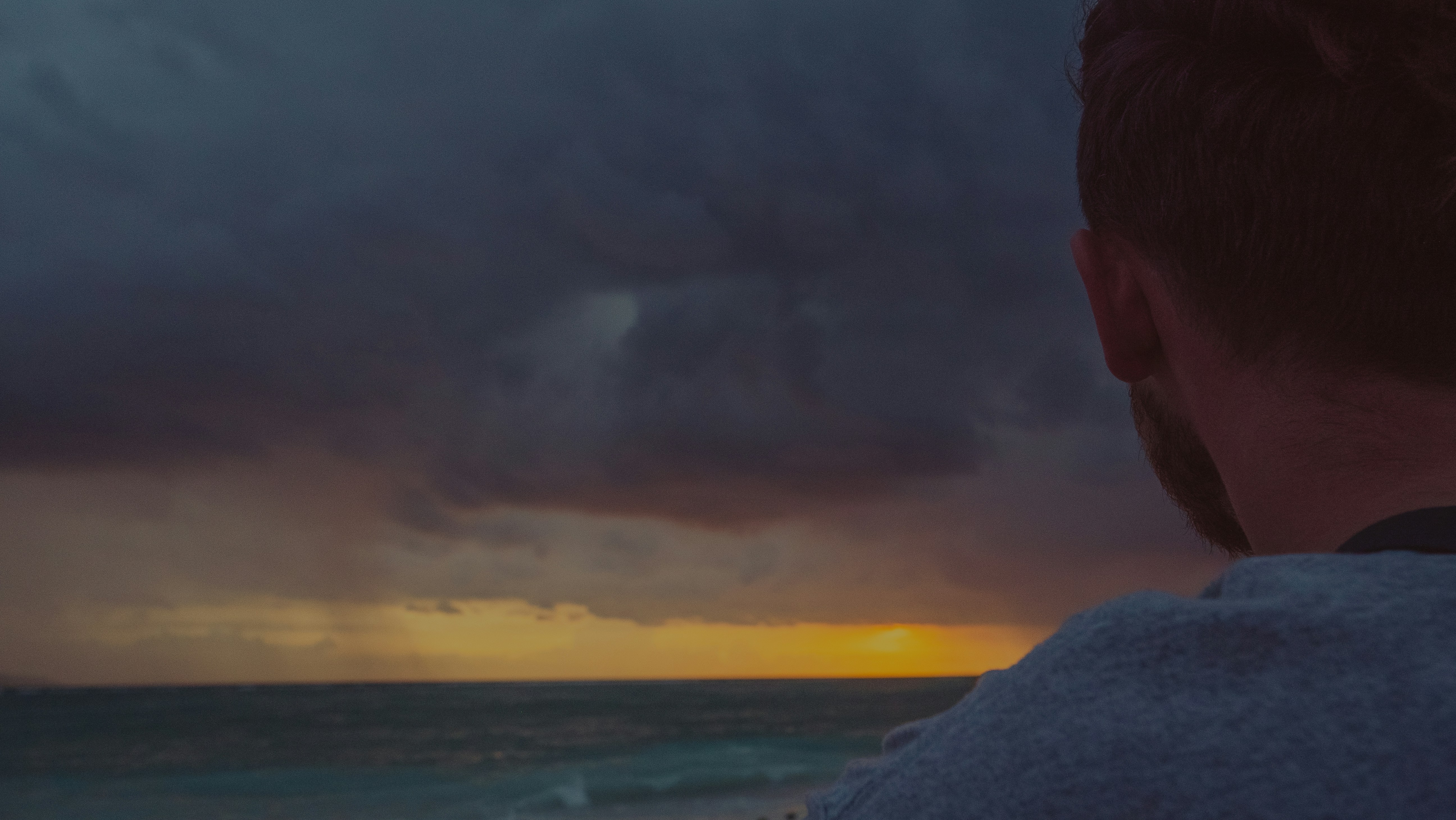 Amber Horizon: A Silhouette Watches the Sea at Dusk