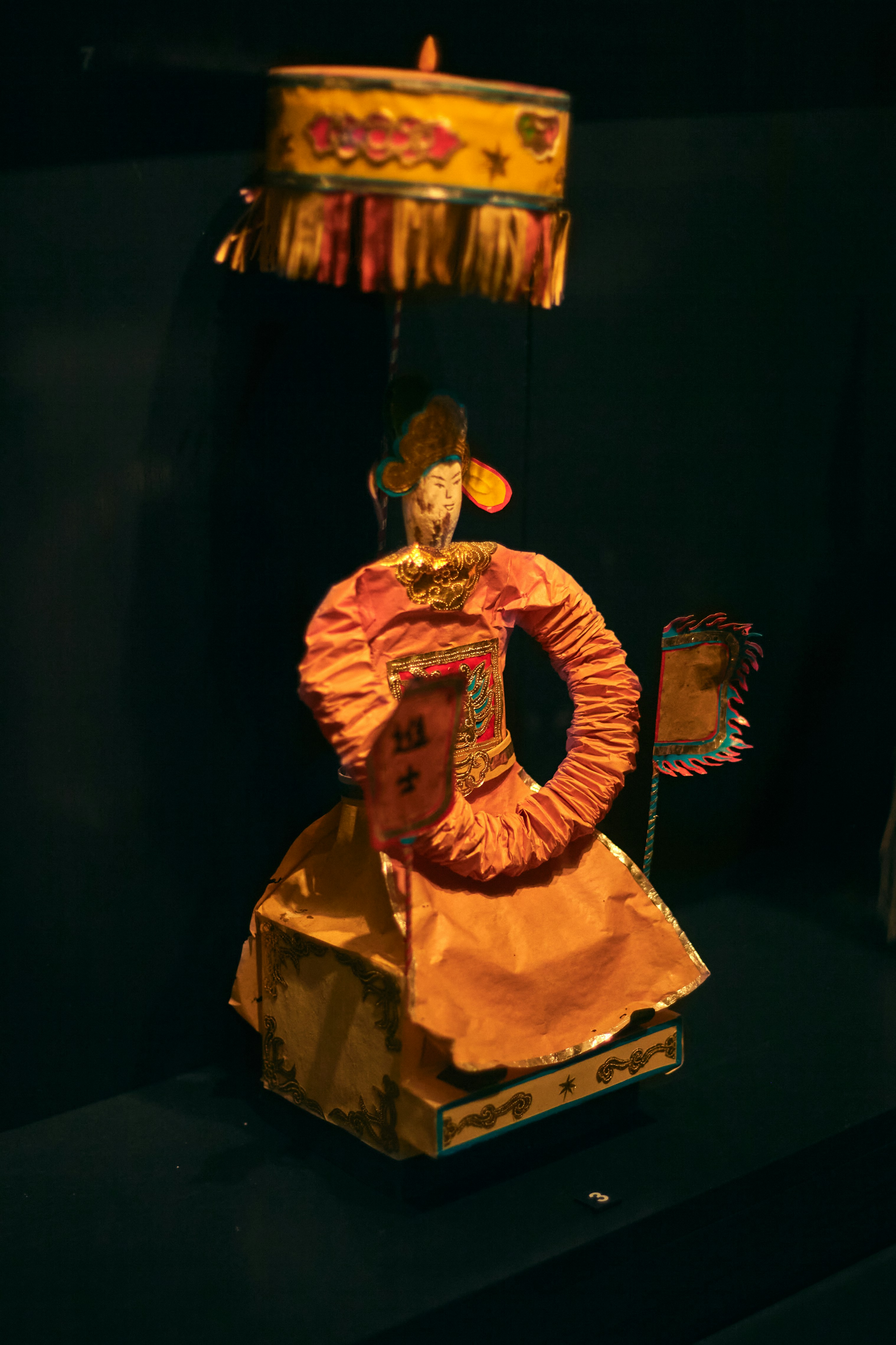 Traditional Vietnamese art and craft displayed in an art museum. | An ornate, antique doll wearing traditional asian attire.