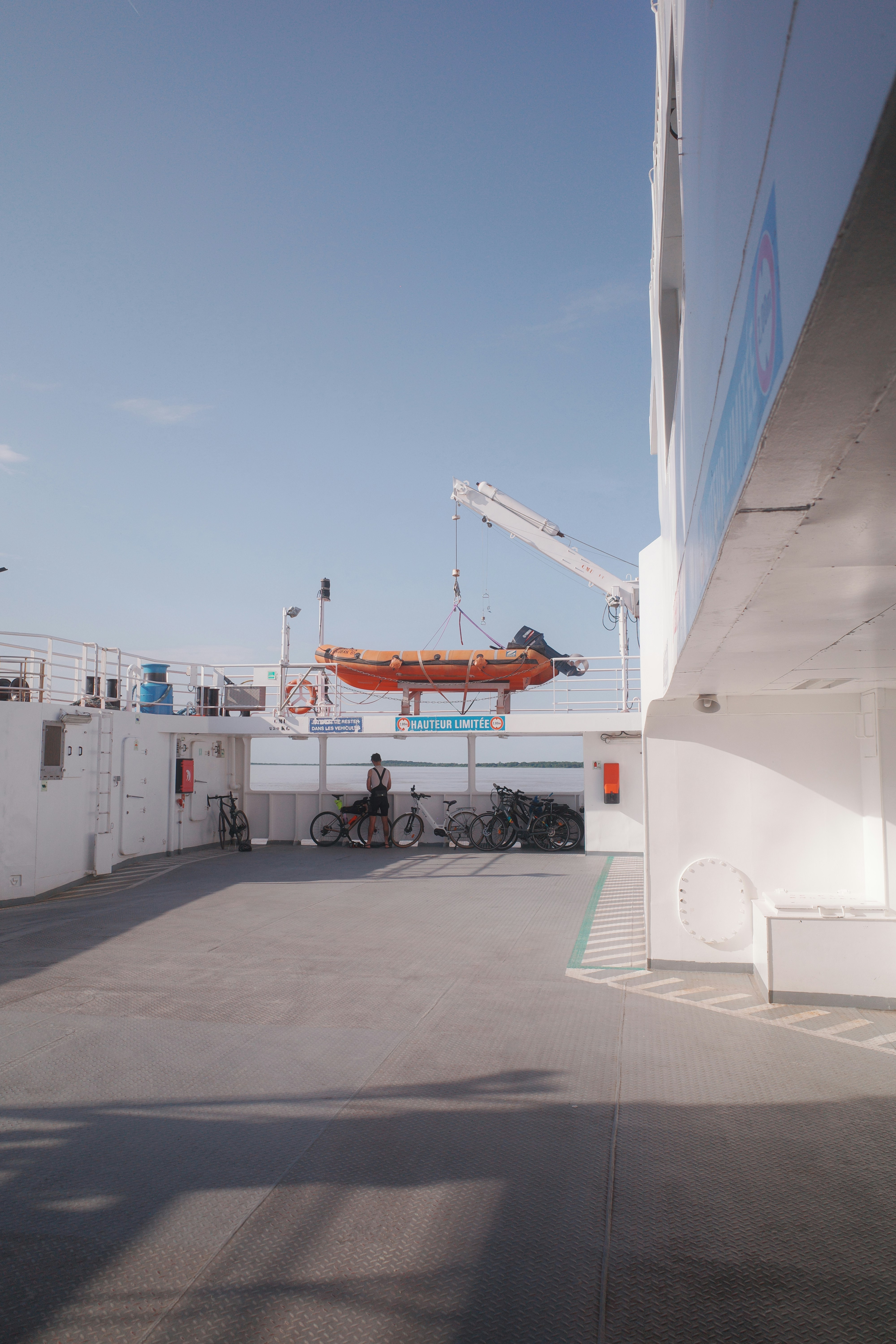 Lifeboat suspended above bicycles on a ferry deck.