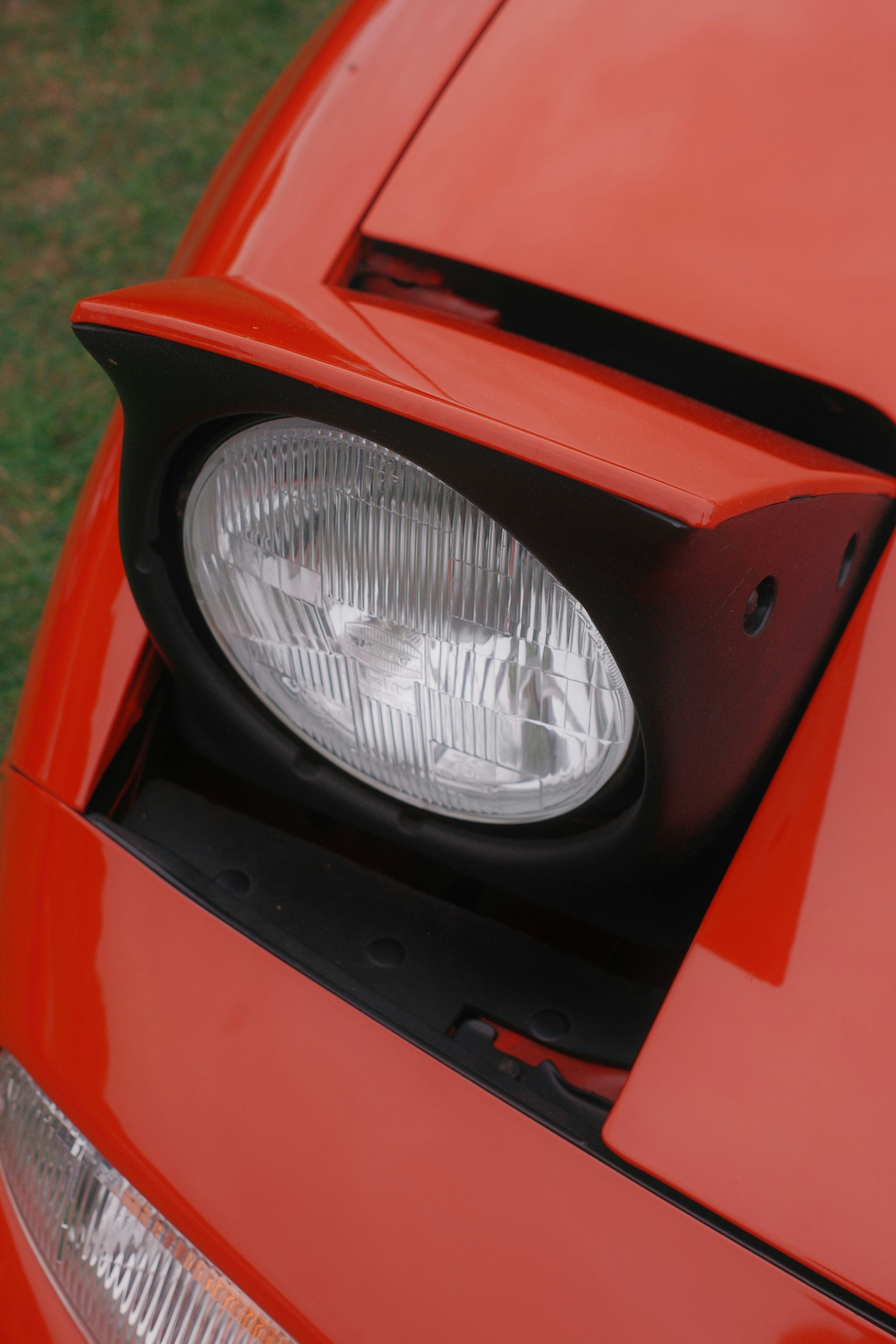 Crimson Precision: Close-Up of a Red Car's Sculpted Headlamp