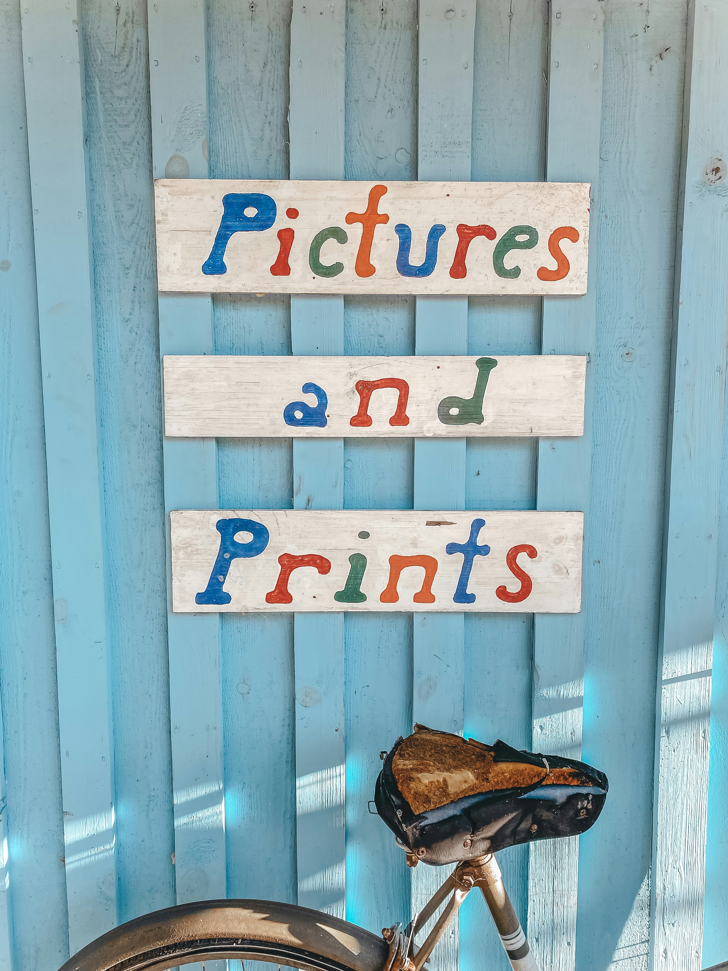 Wooden sign with colorful letters reads pictures and prints.
