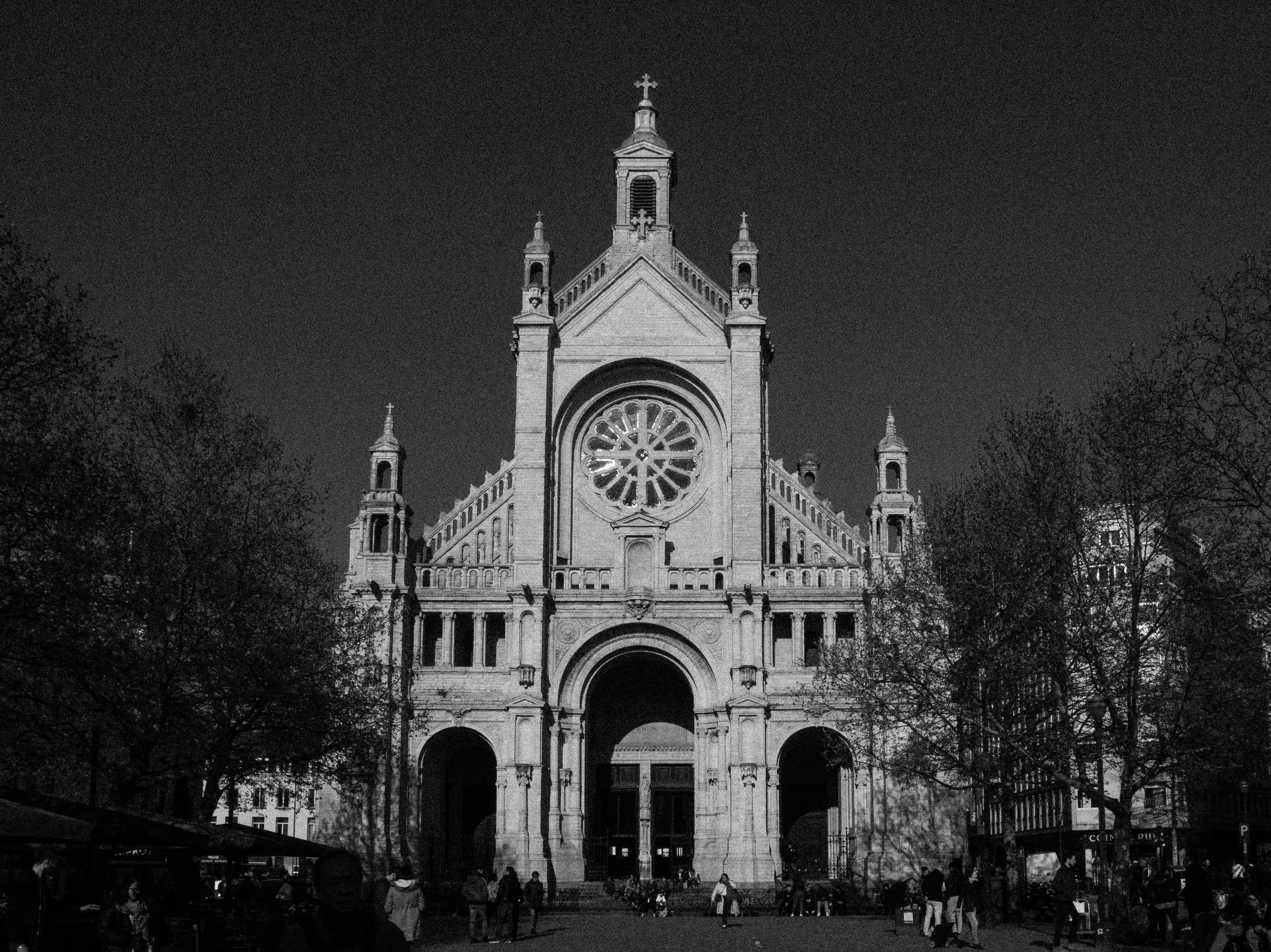 Grand church facade with arched entrance and rose window.