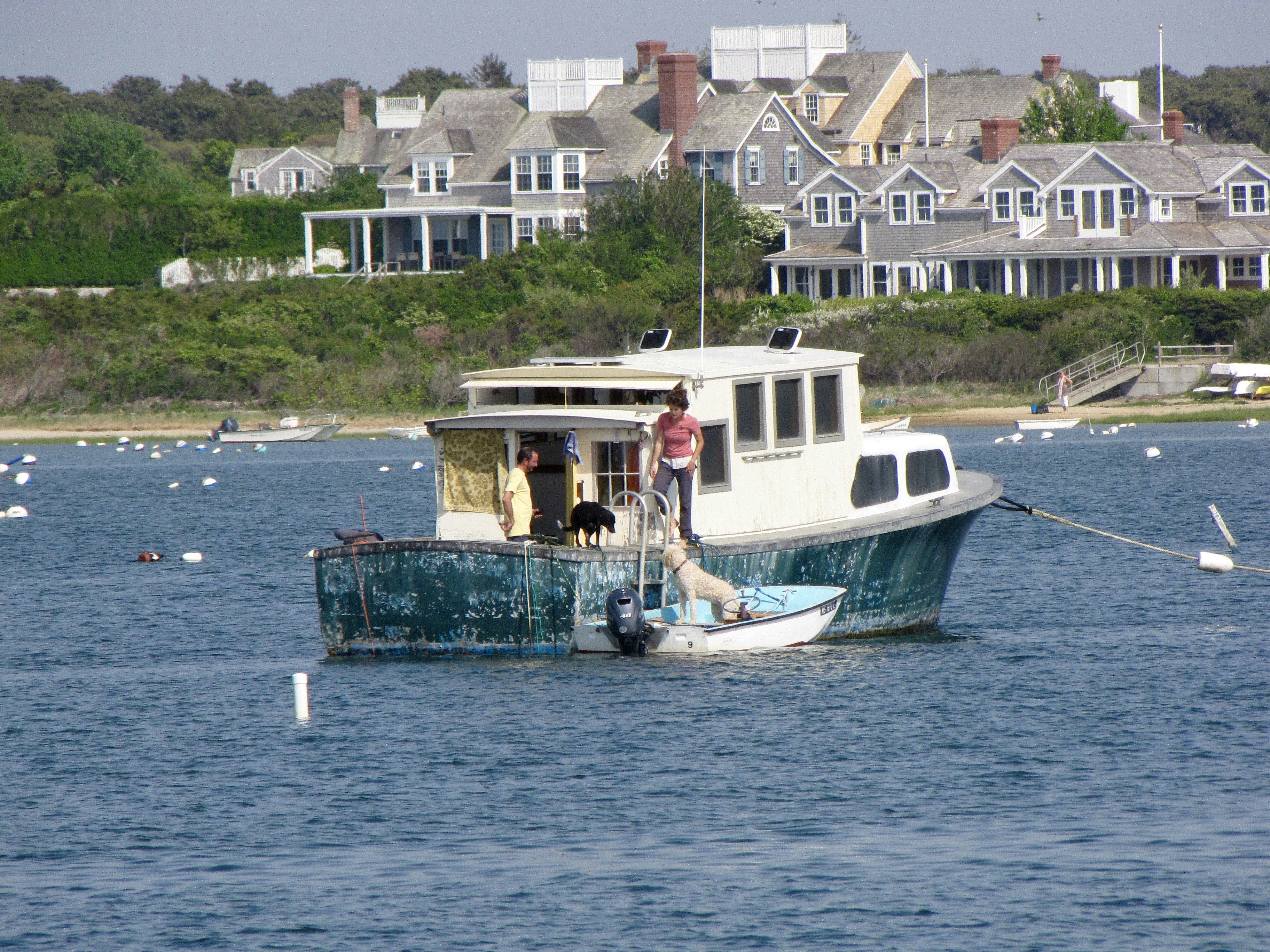 Boat docked in the water with houses behind