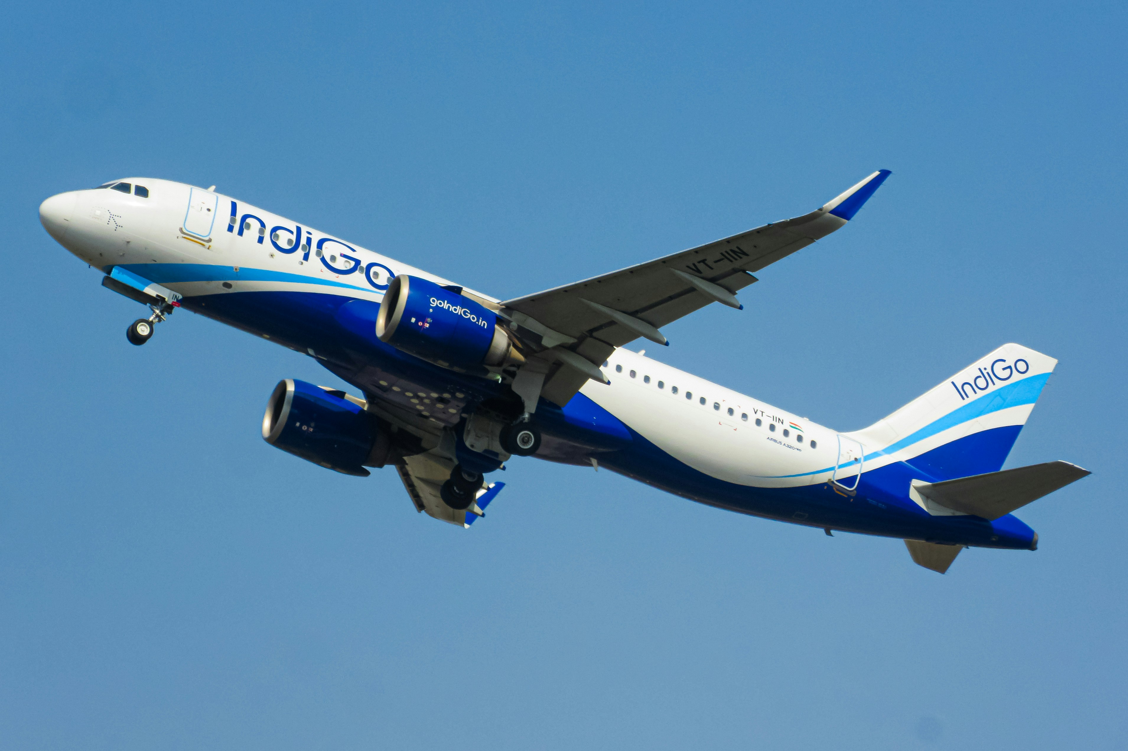 IndiGo aircraft ascending against a clear blue sky, showcasing its vibrant livery and aerodynamic design.