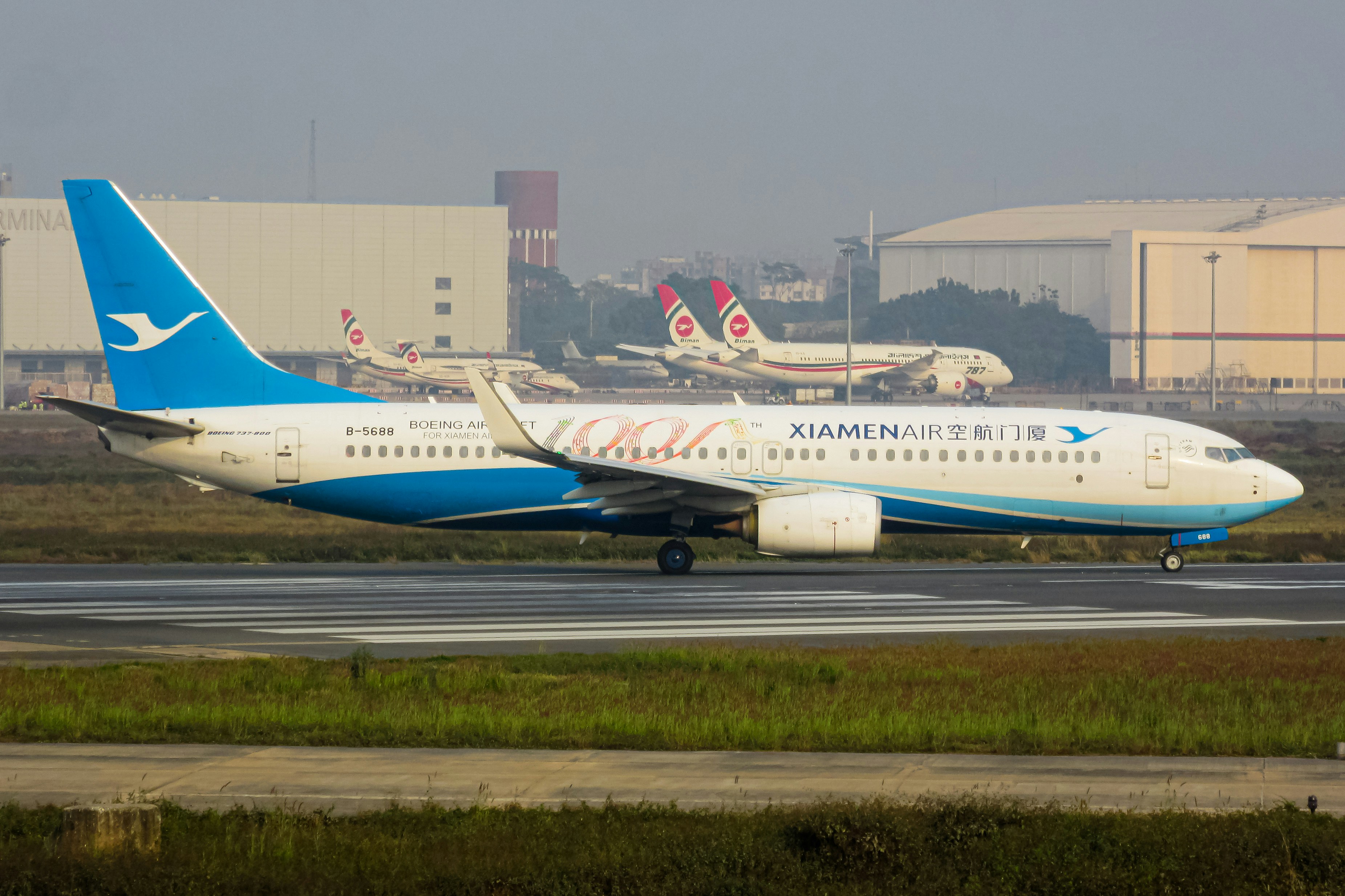 XiamenAir Boeing 737 taxiing on the runway with other aircraft in the background. The scene captures the dynamic environment of an airport.
